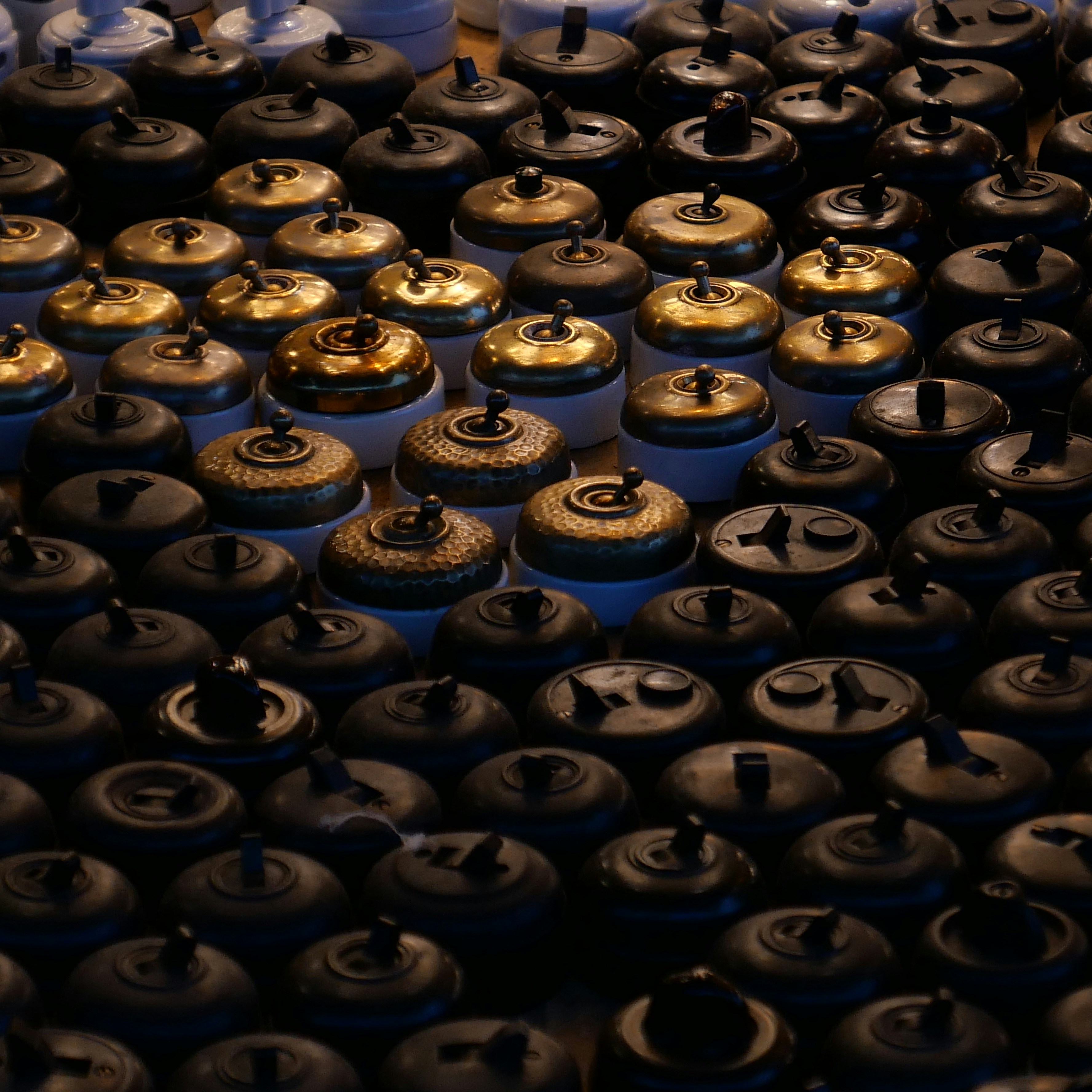 Rows of spray-paint can lids arranged in a tight grid, with a warm center glow highlighting a cluster of brass-blue caps.