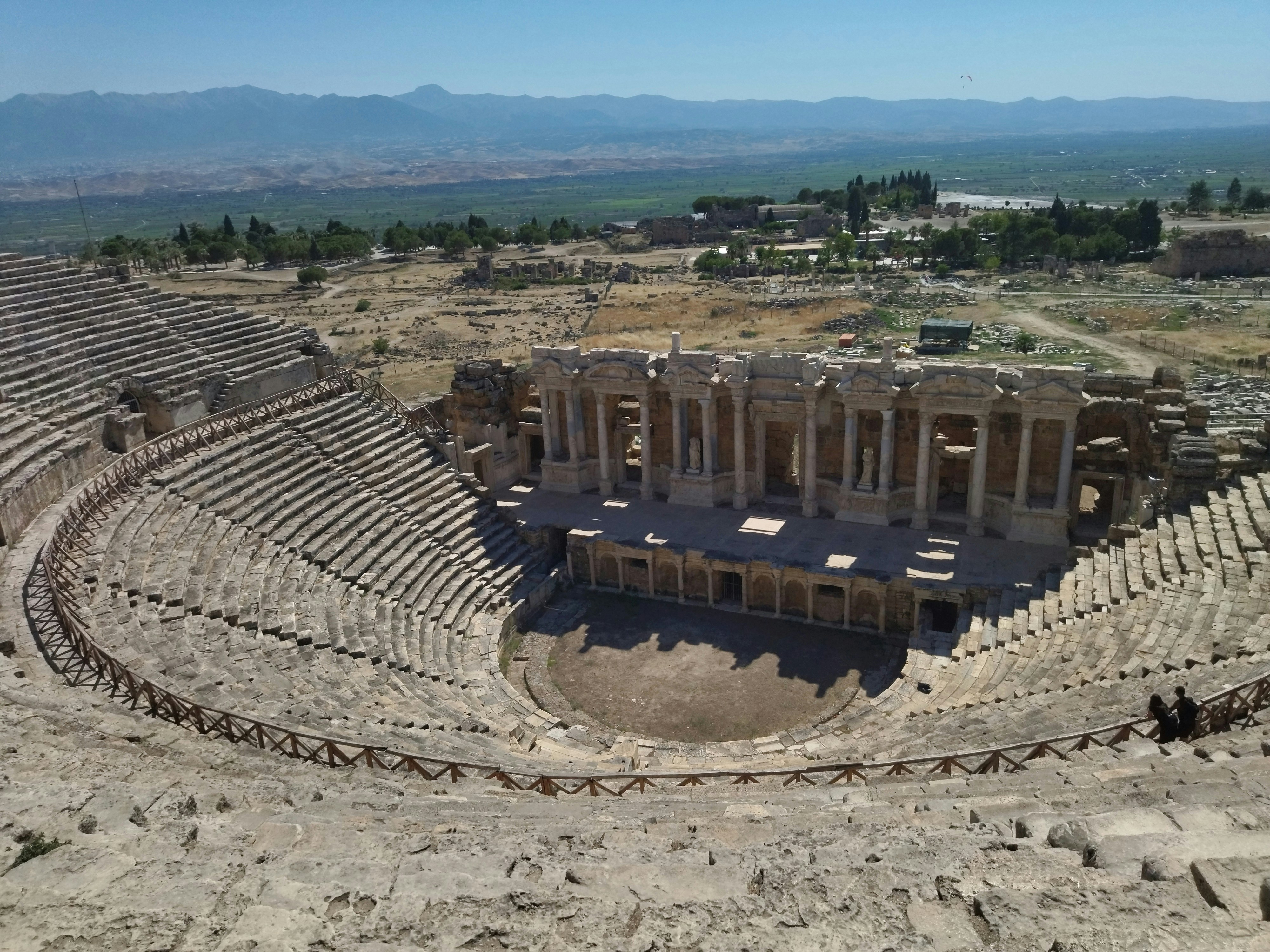 Ancient stone amphitheater with tiered seating under a clear blue sky.