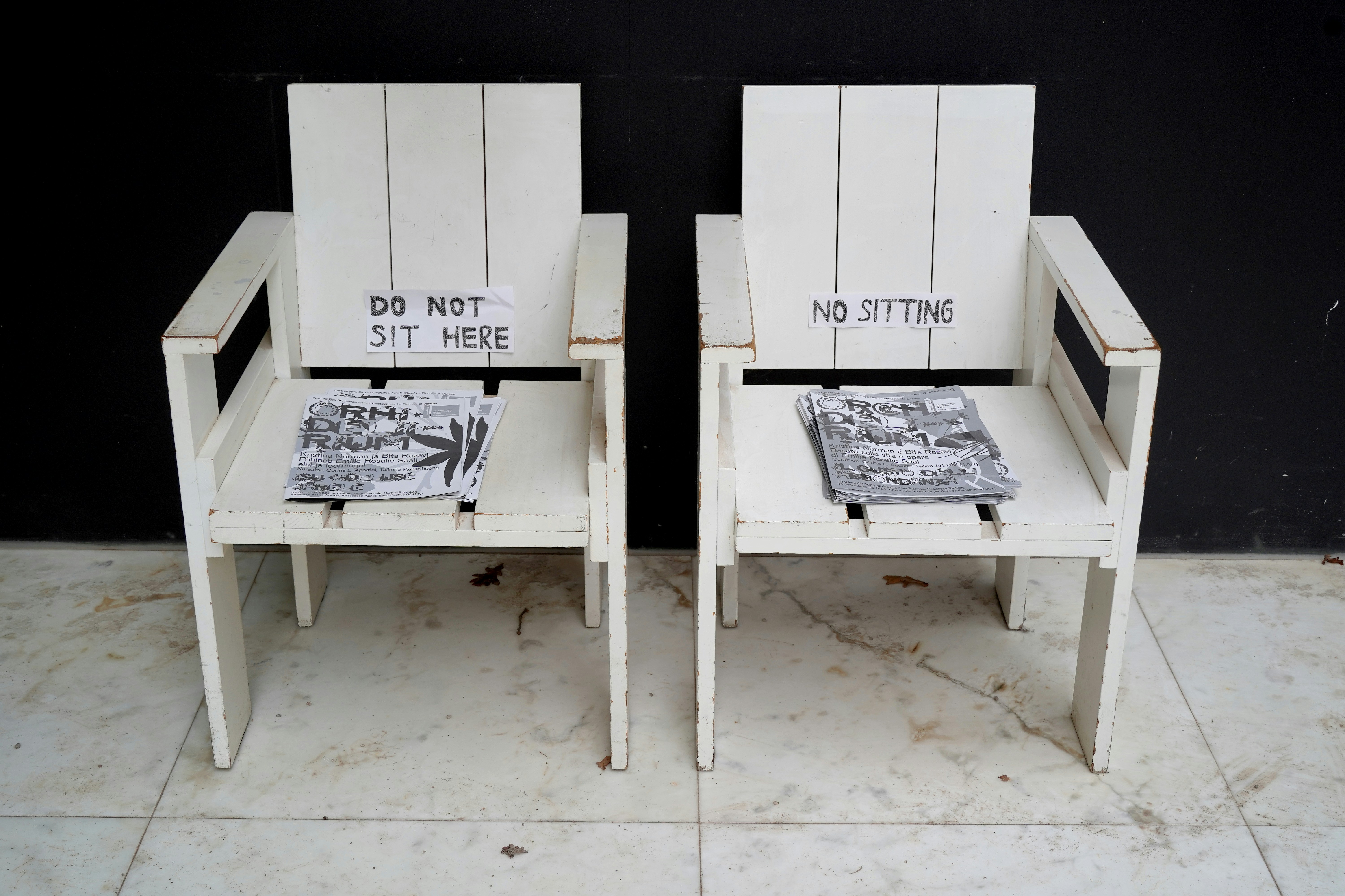 Silent Boundaries: Two White Chairs Mark No-Sit Borders with Monochrome Magazines