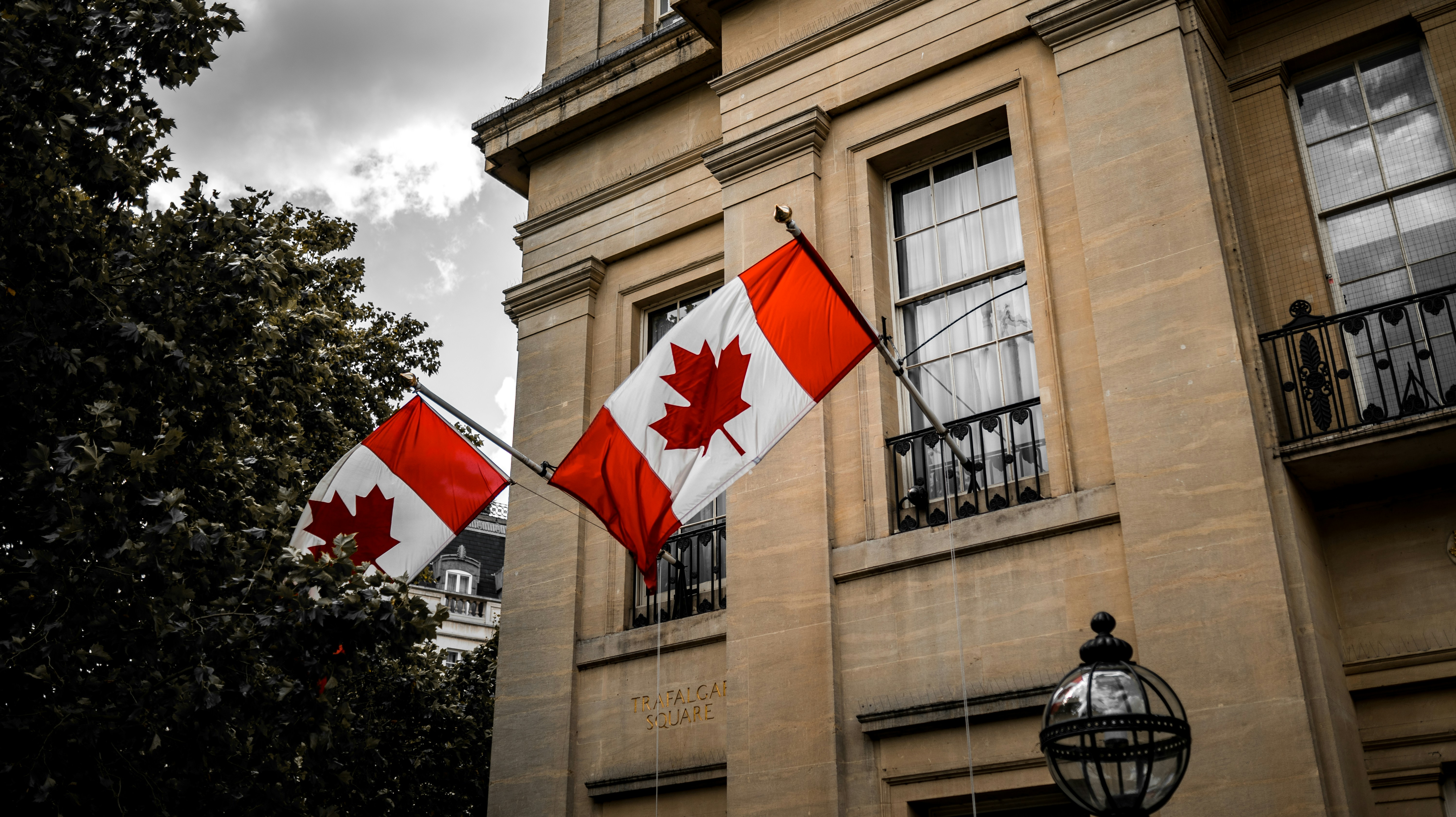A few flags flying in front of a building photo – Free Flag Image on ...