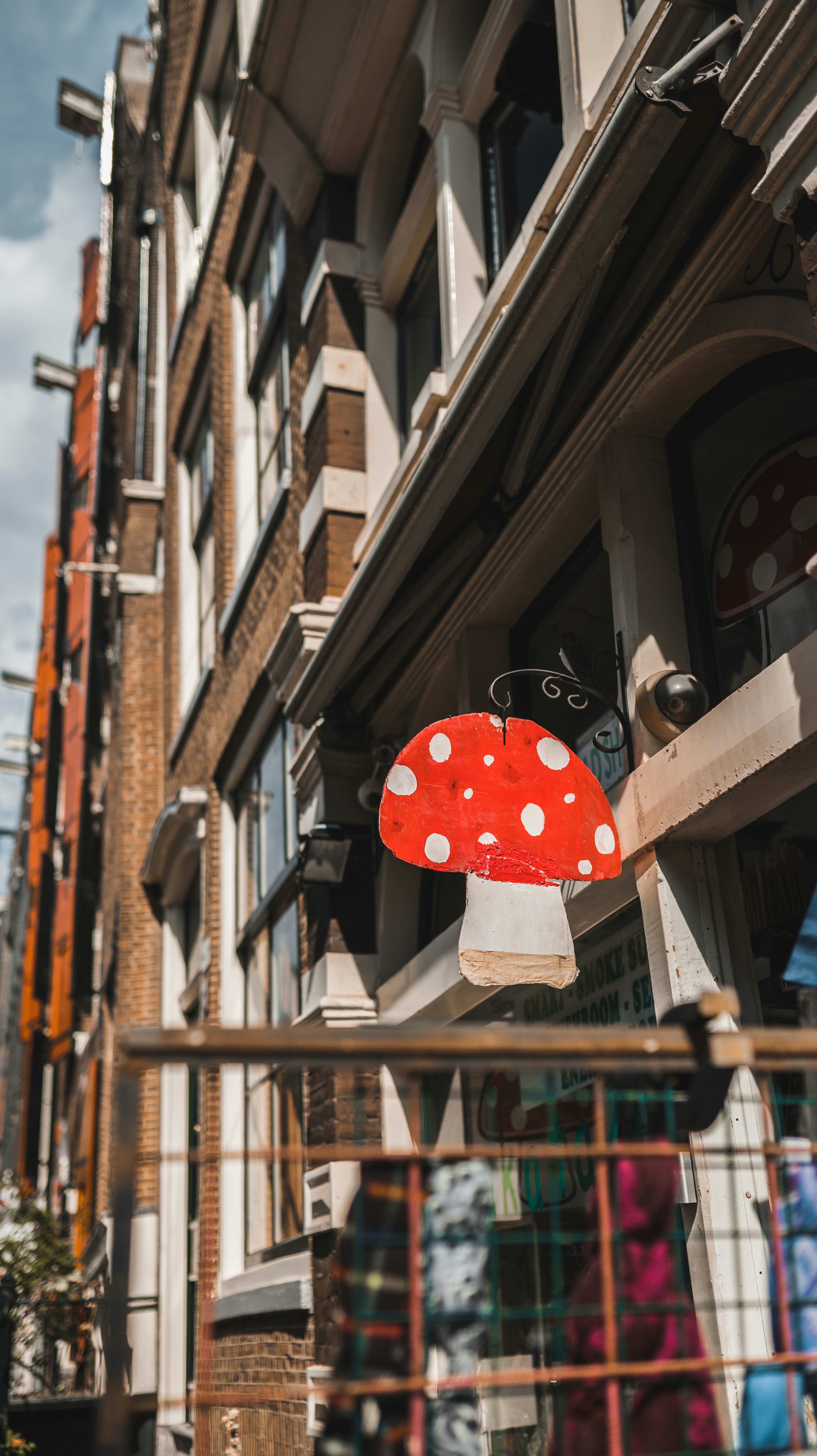 Whimsical Mushroom Sign Anchored to a Brick-Front City Street