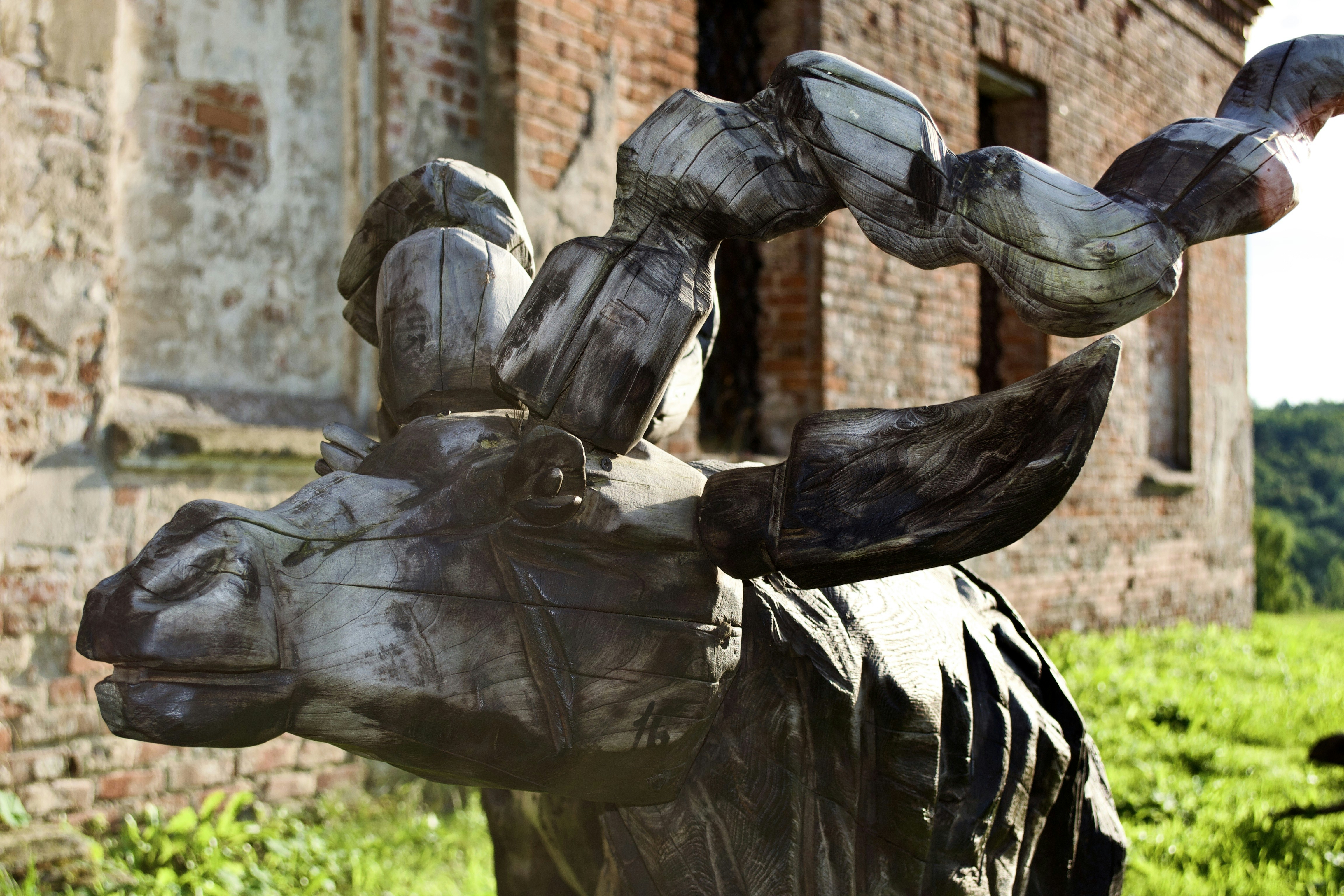 Iron Serpent at the Ruin: A Metal Sculpture Framing a Weathered Brick Wall