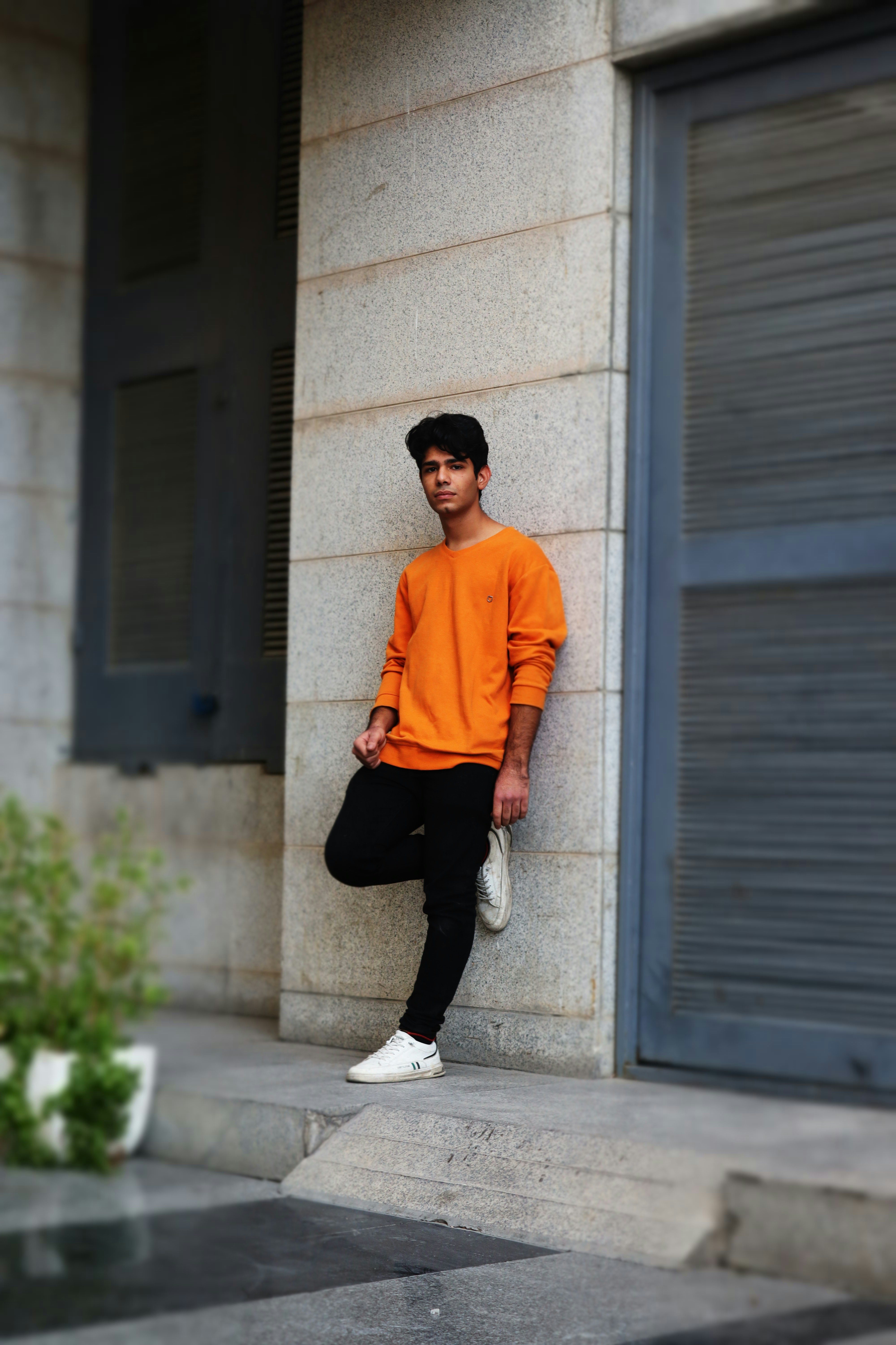 Orange Sweatshirt, Concrete Frame: A Casual Stance Against Urban Stone