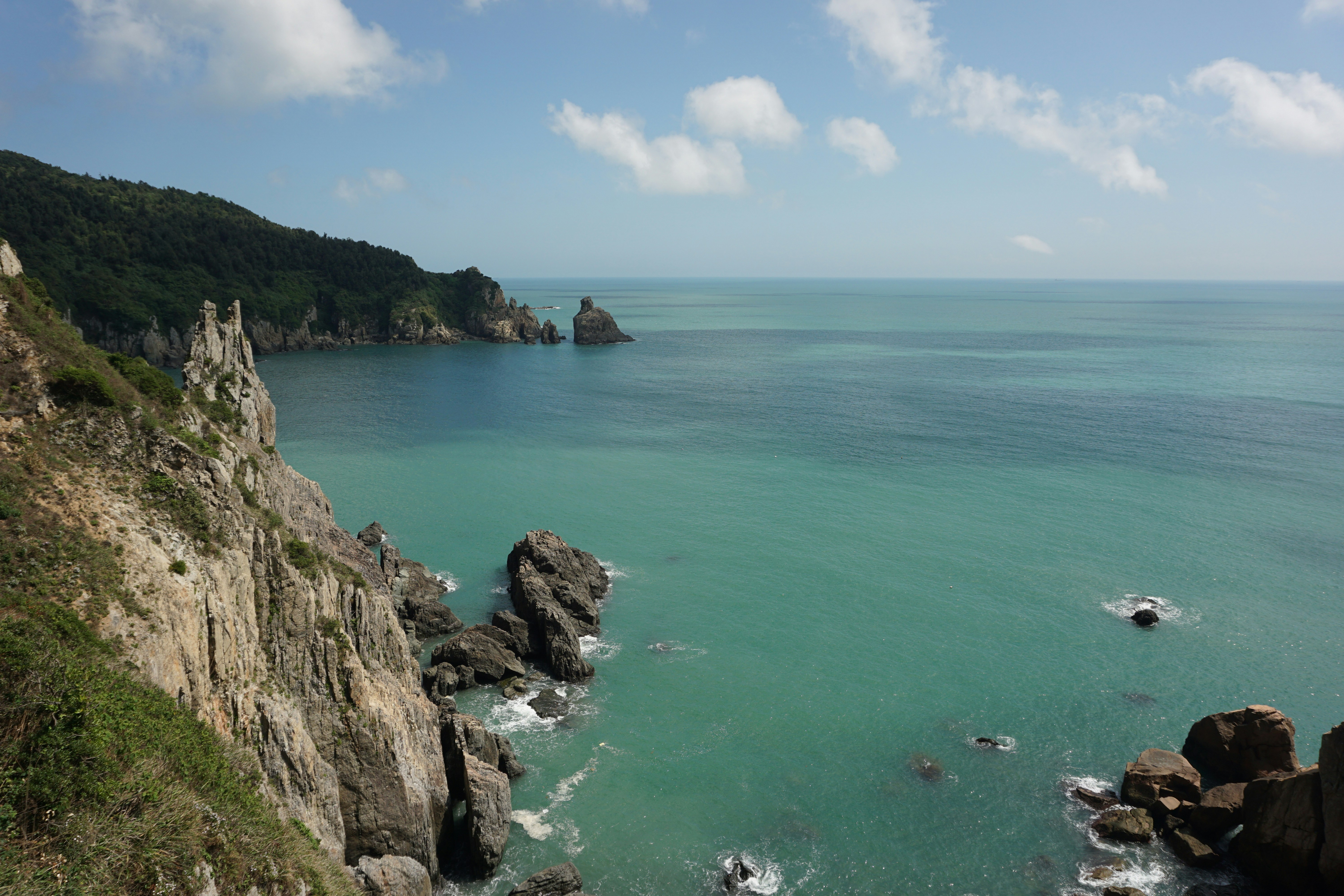 Cliffside Cascade: Turquoise Sea Meets Rugged Shore