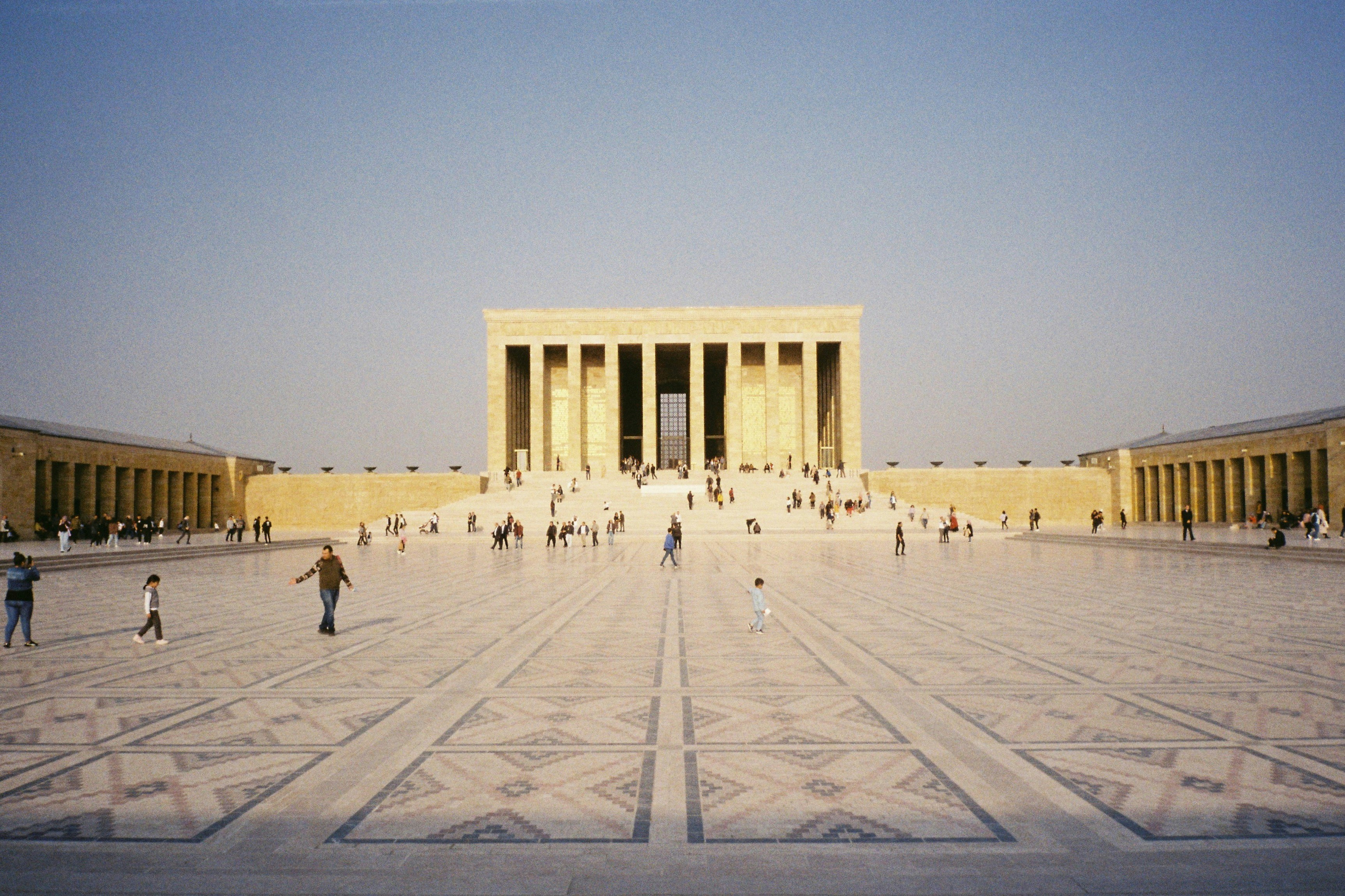 Expansive plaza leading to a grand mausoleum under a clear blue sky.