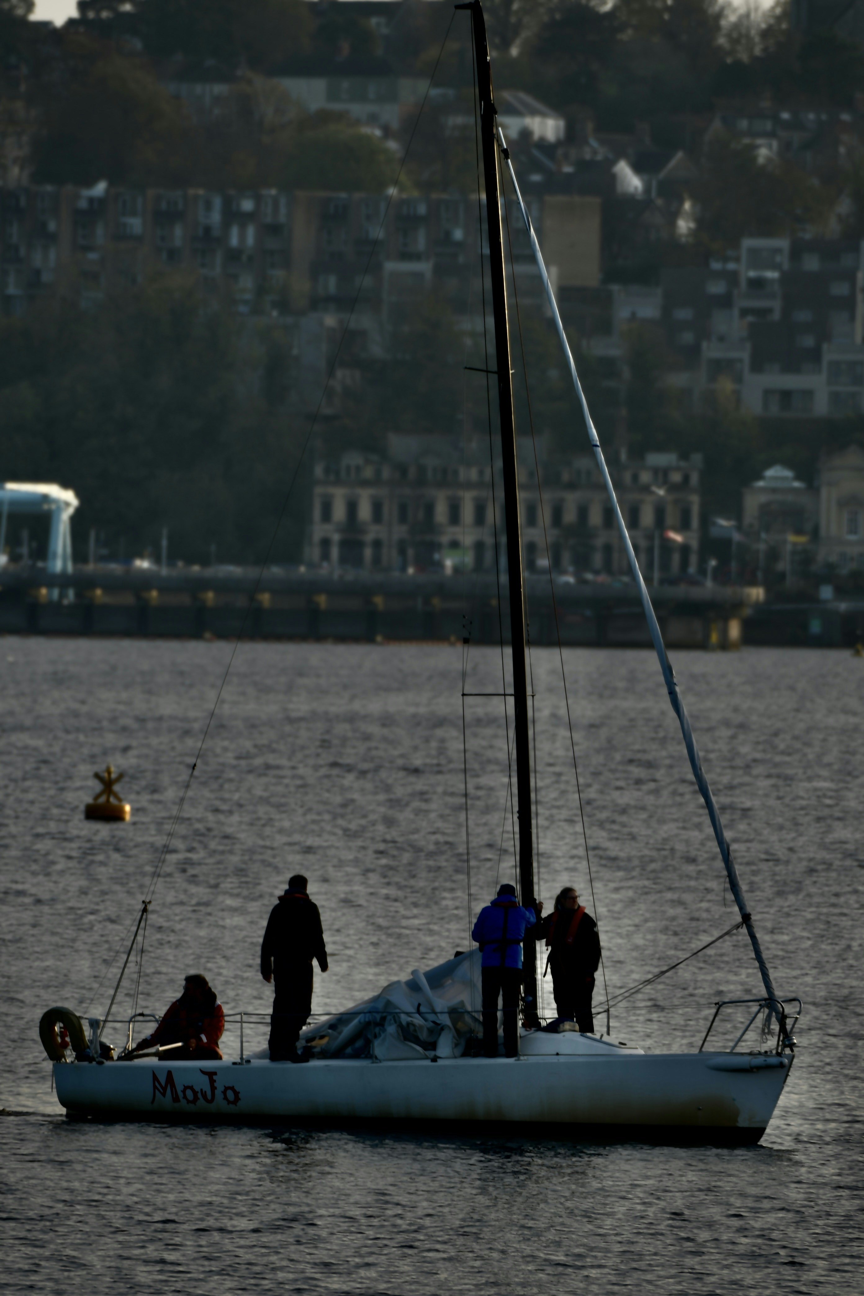 MoJo at Dusk: A Sailboat Threads the Quiet Harbor Under City Lights
