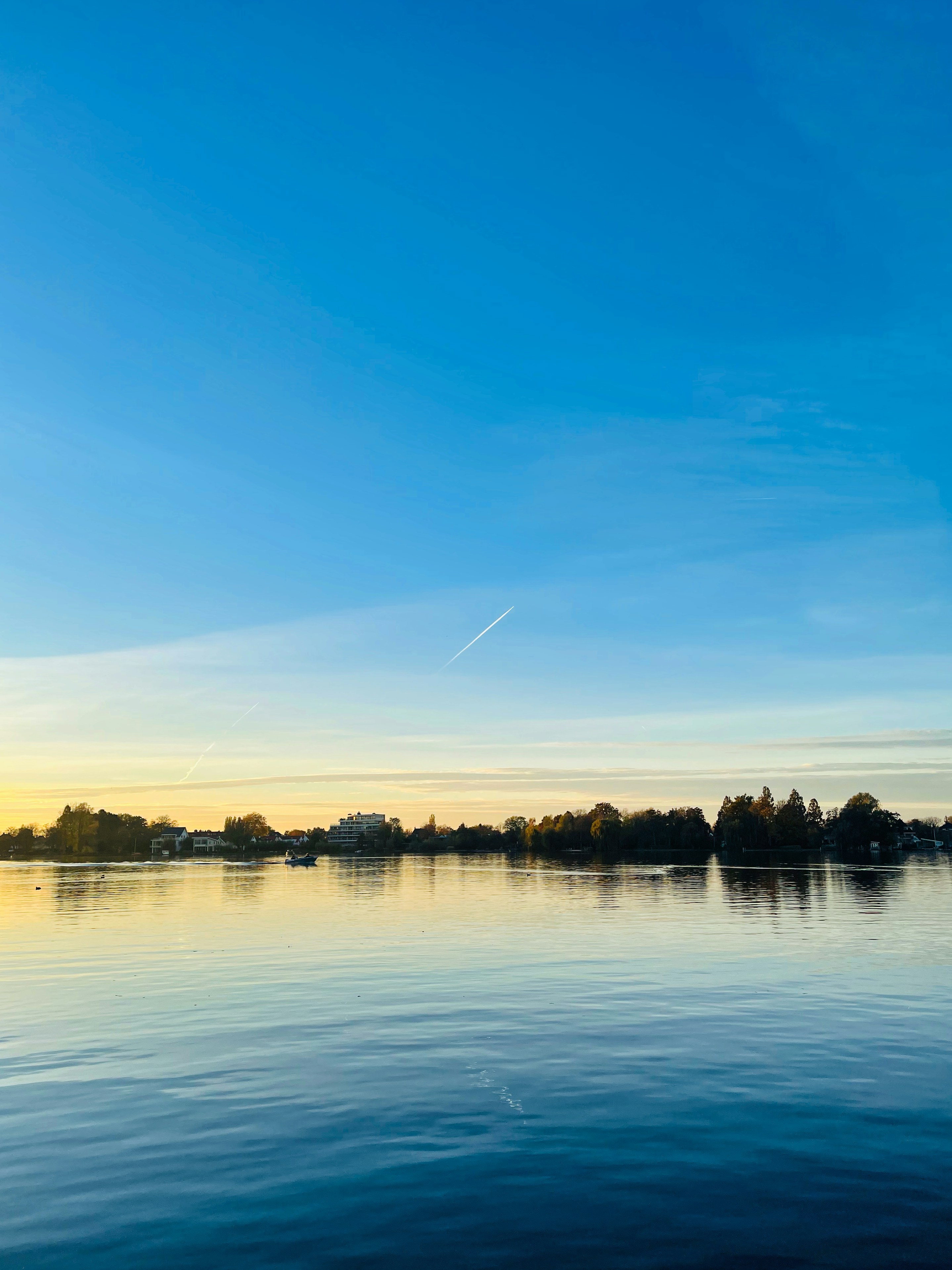 Contrail Silhouette Over a Quiet Lake at Dusk