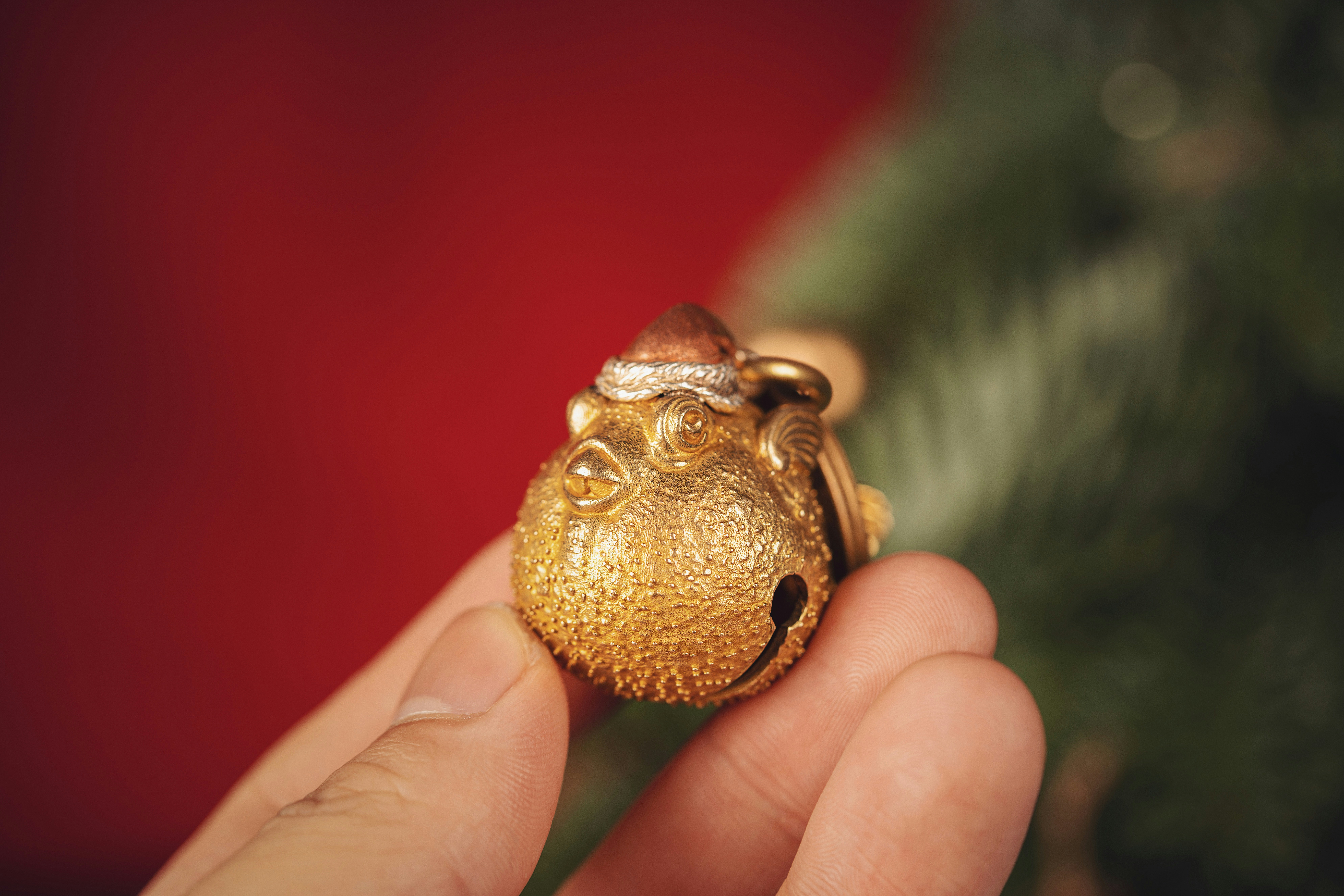 Tiny Gold Nutcracker Ornament Held Between Fingers in Warm Holiday Glow