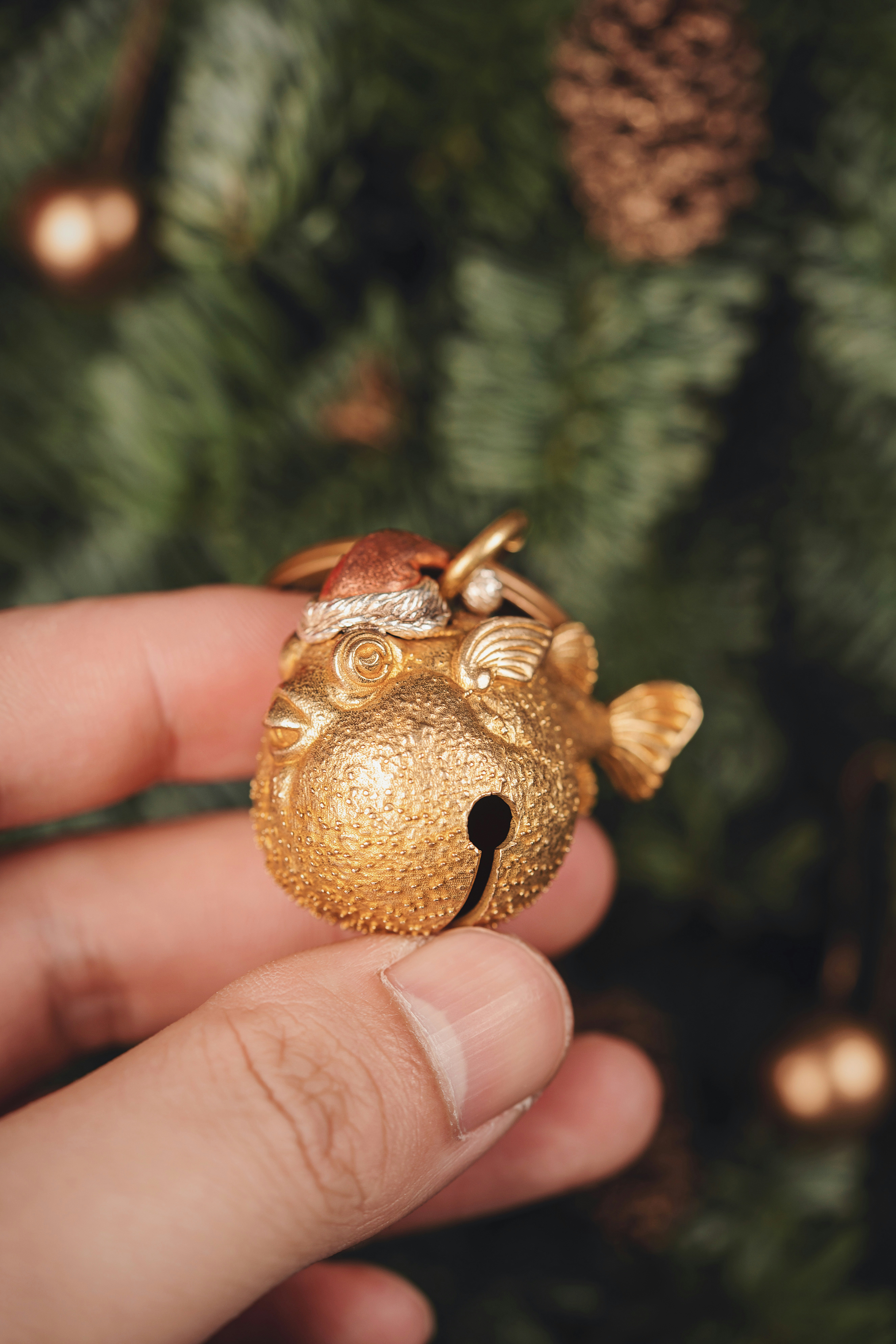 Gold Bell Ornament: A Tiny Locket Held Near a Christmas Tree