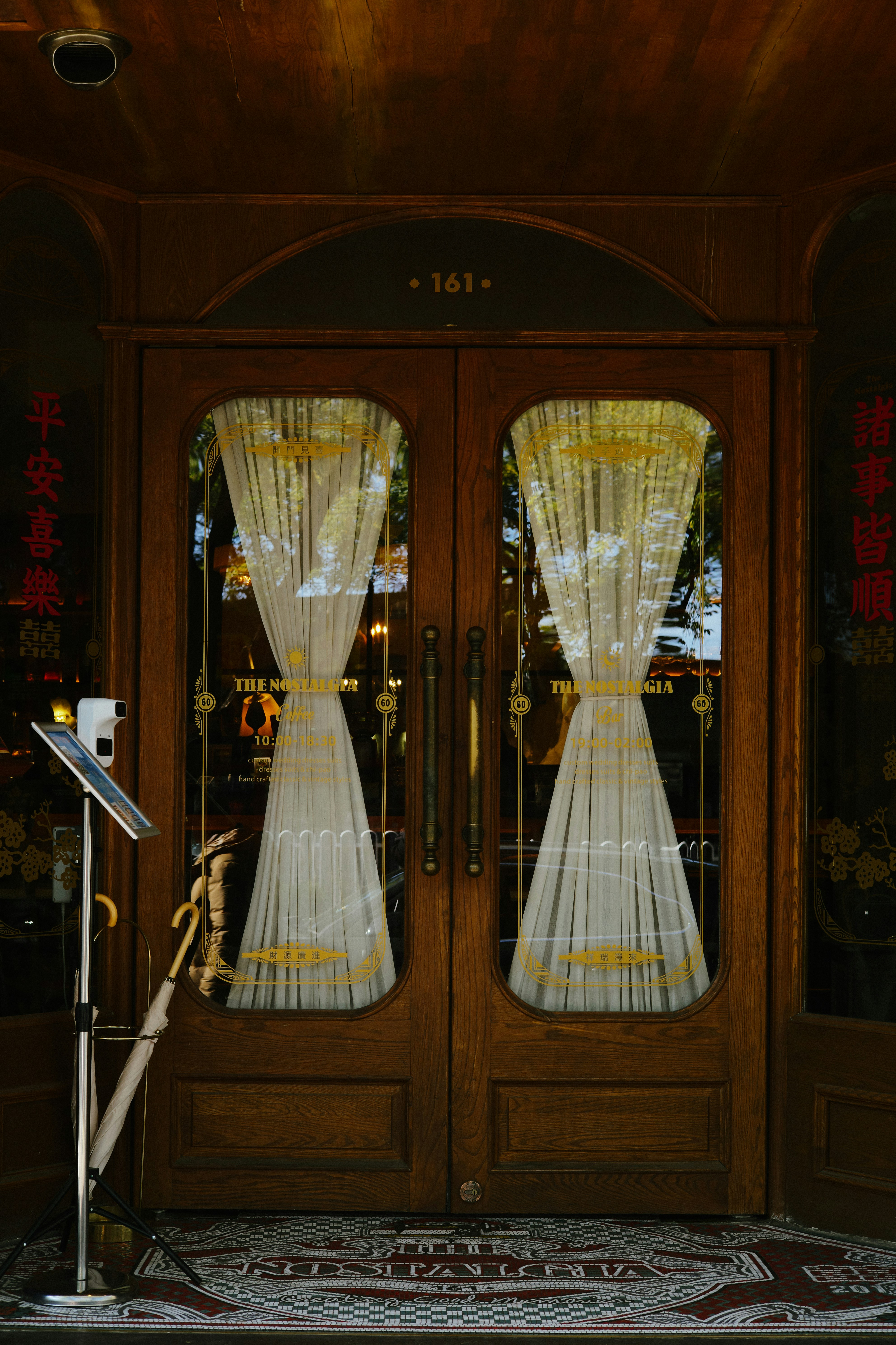 Ornate wooden double doors adorned with sheer curtains and golden accents, inviting patrons into a charming establishment.