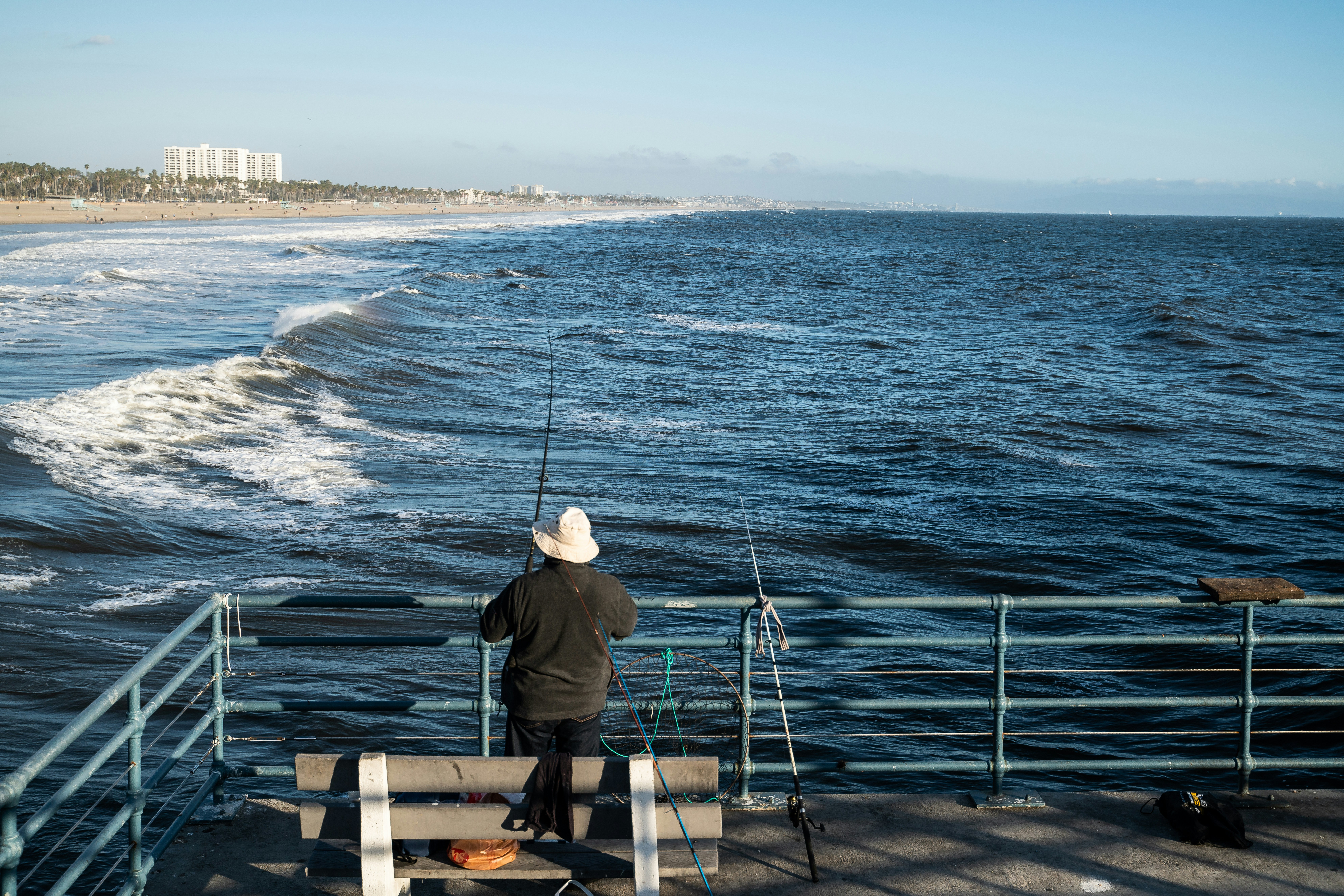 End of the Pier: Lone Angler Casts Into a Blue Sea