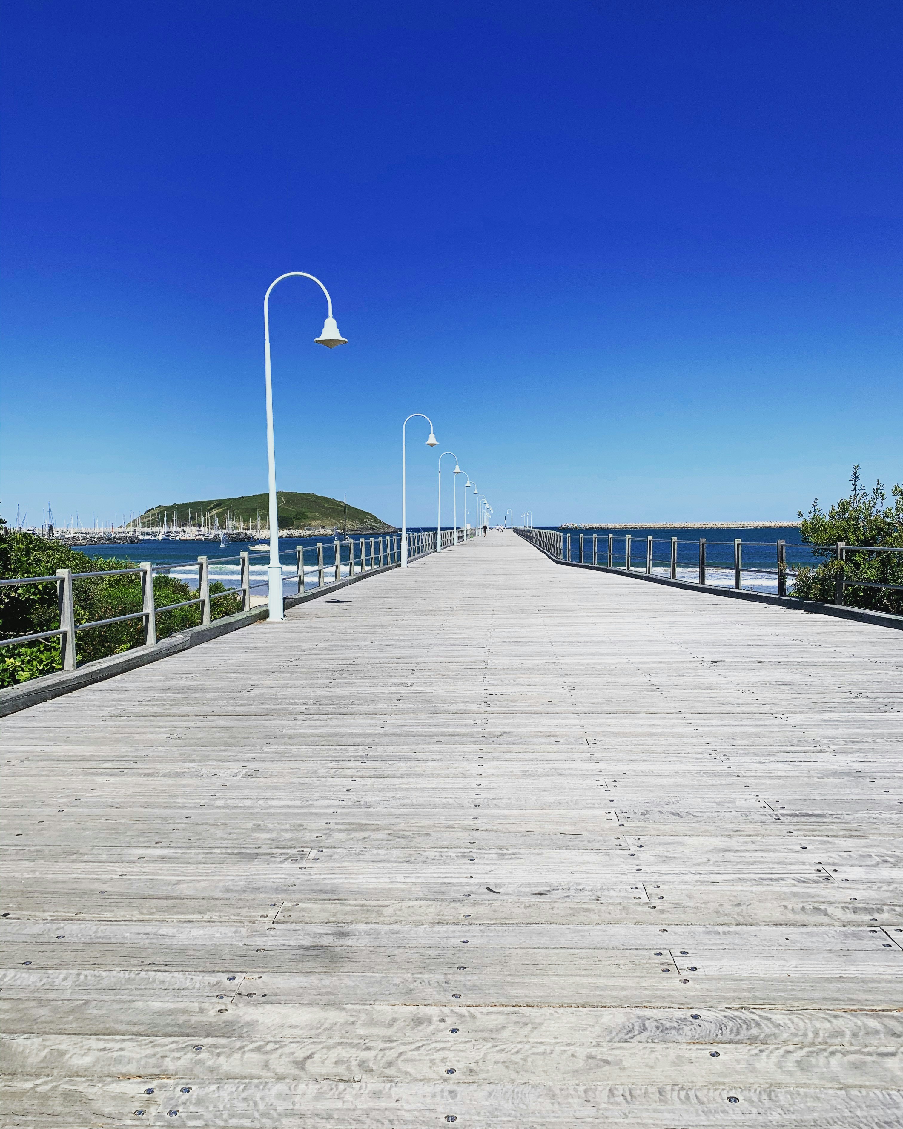 A boardwalk with light posts and a body of water in the background ...