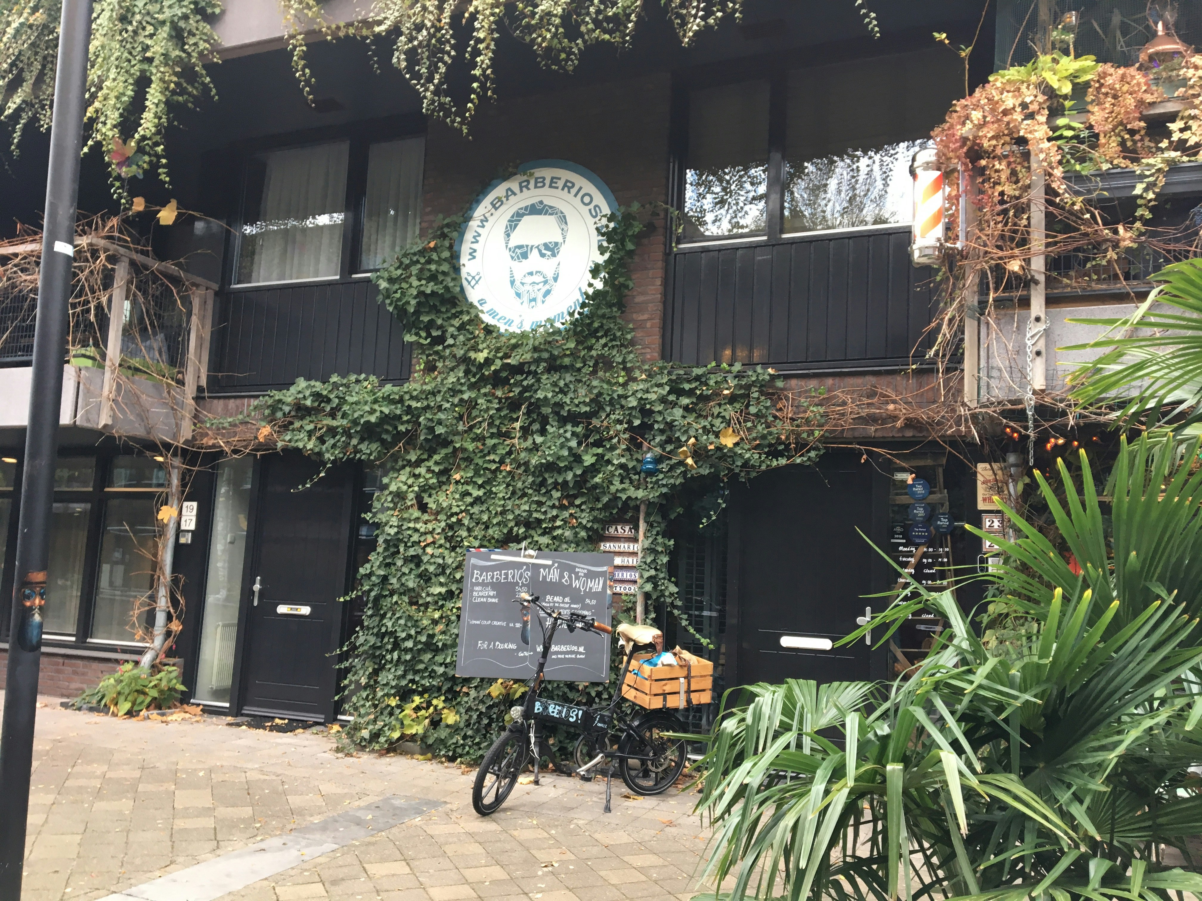 Building exterior with lush vines and plants enveloping the entrance, featuring a bicycle parked nearby.