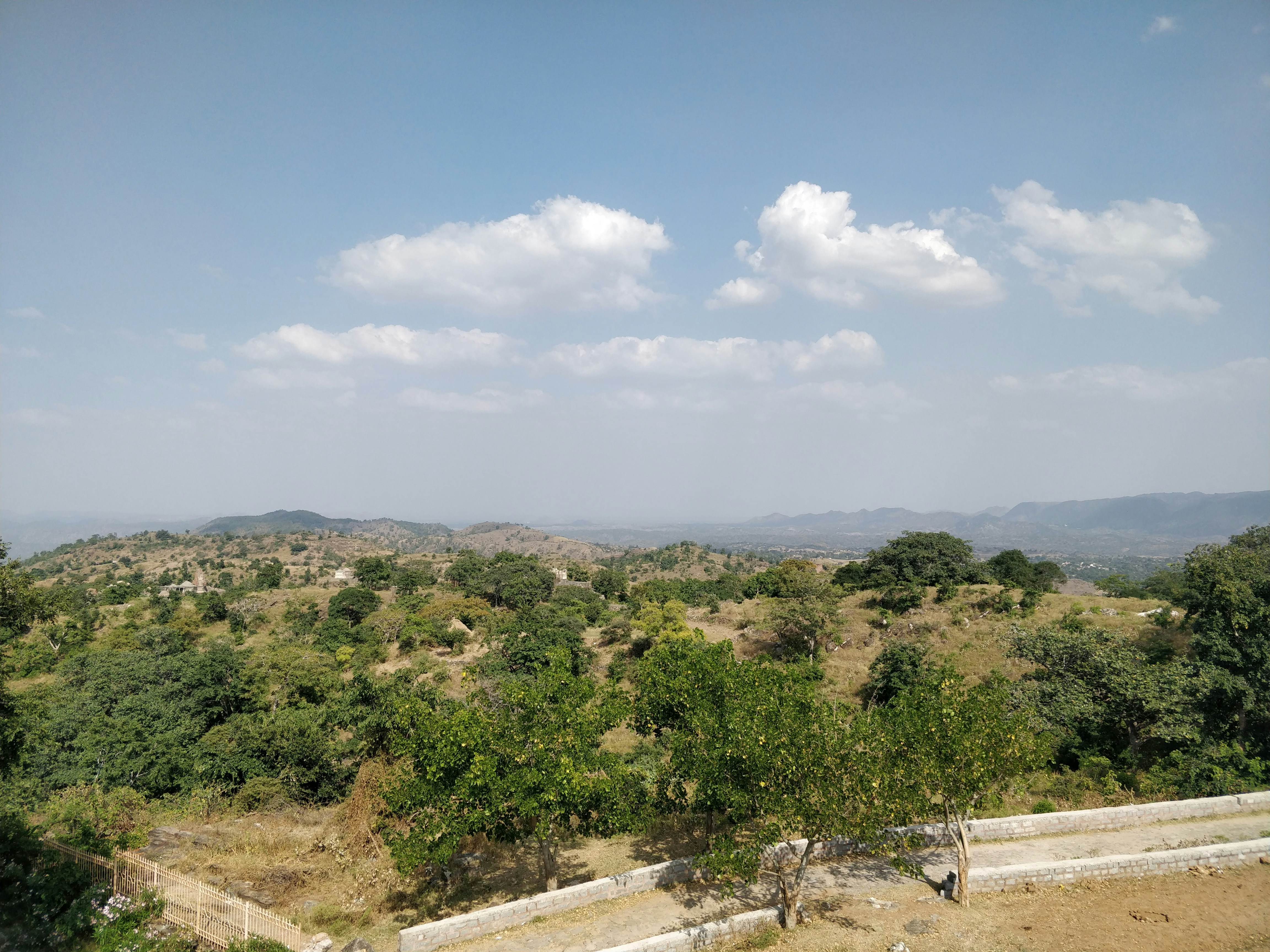 Lush green hills under a bright sky dotted with clouds, showcasing the beauty of nature's tranquility.