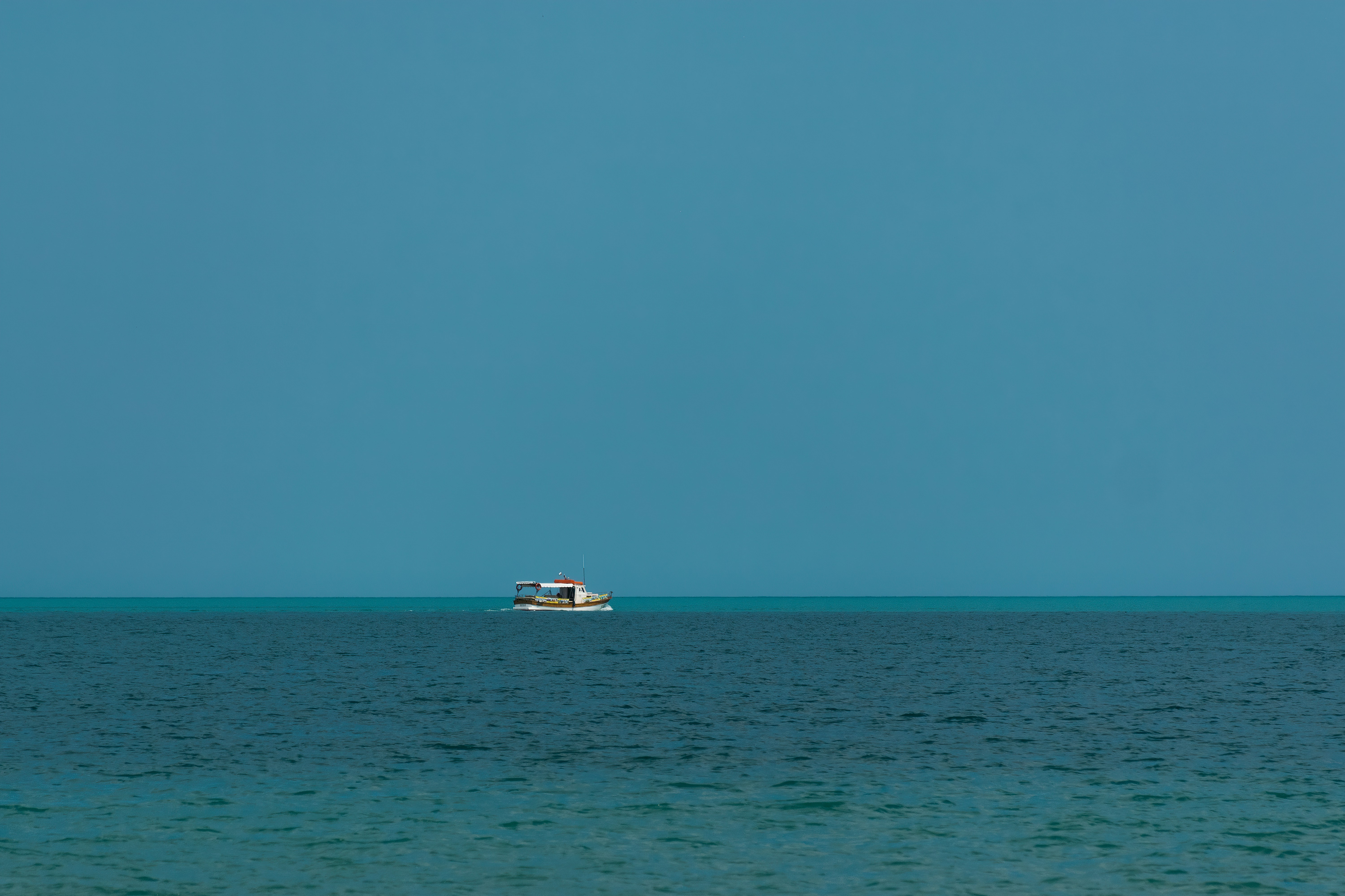 Azure Horizon: A Lone Boat at Sea