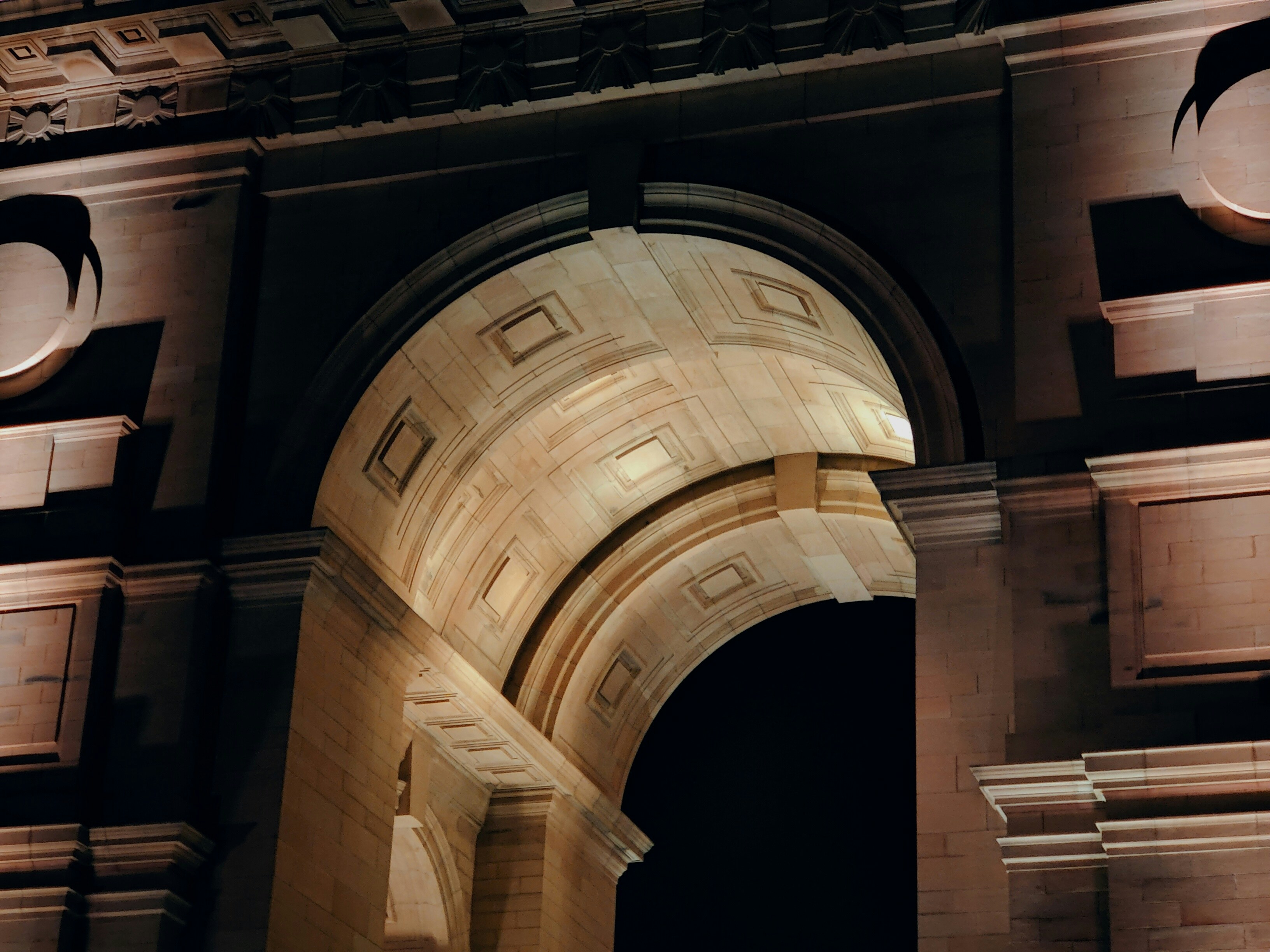 Architectural archway illuminated against a dark sky, showcasing intricate stonework and design details.