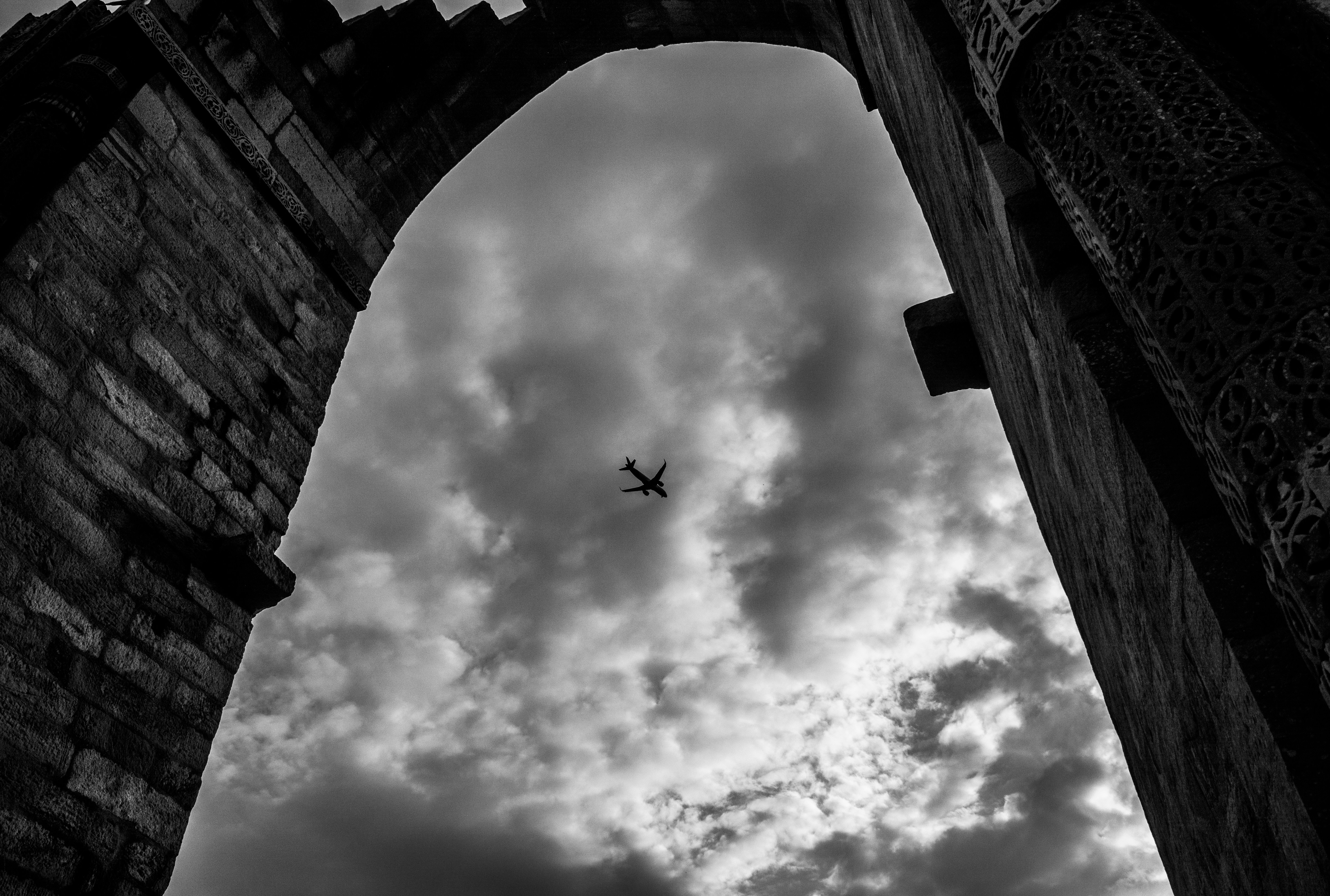 Flight Through the Arch: A lone jet carving a path through a storm-lit sky