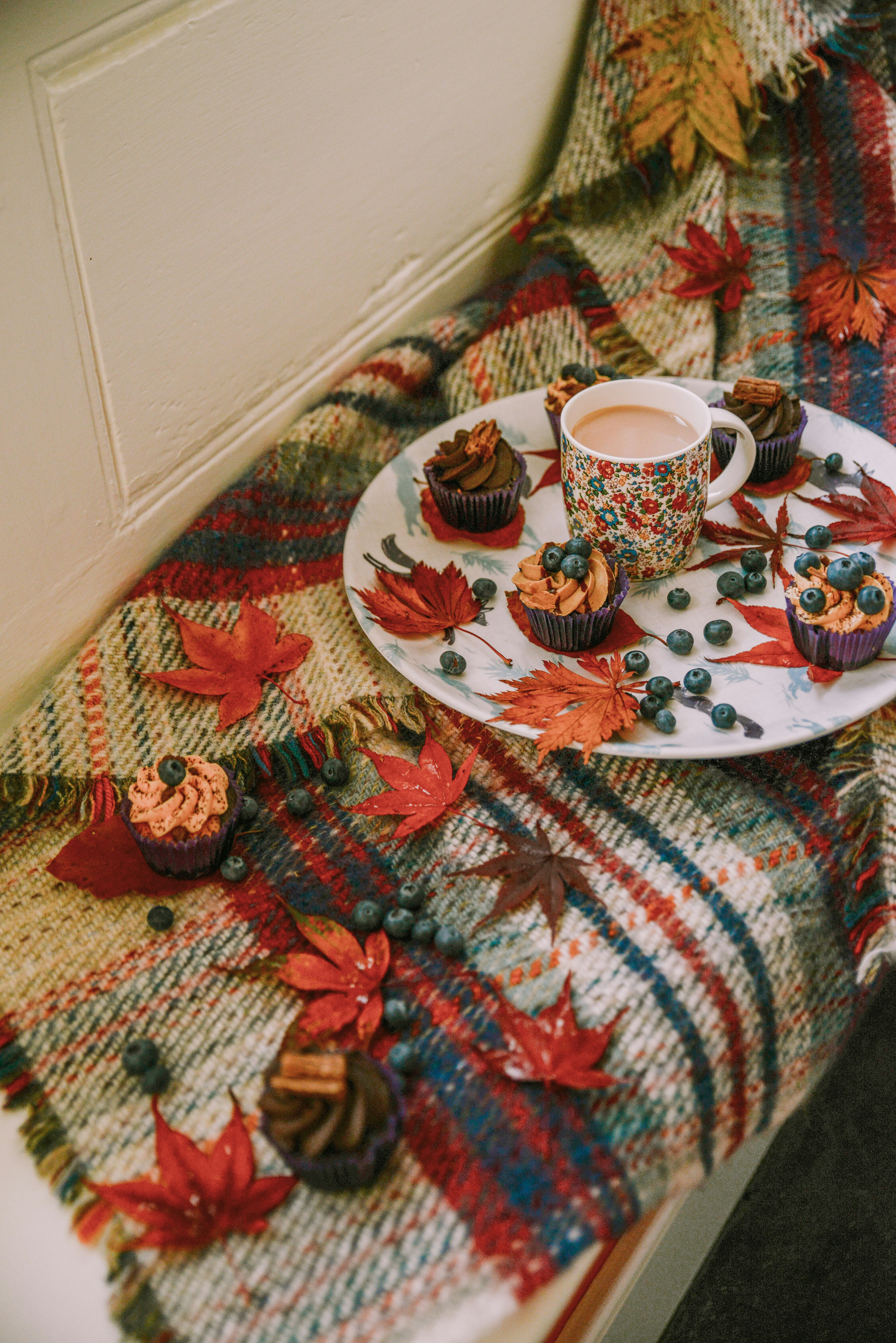 Autumn Tea Moment: Floral Mug and Cupcakes on a Plaid Blanket