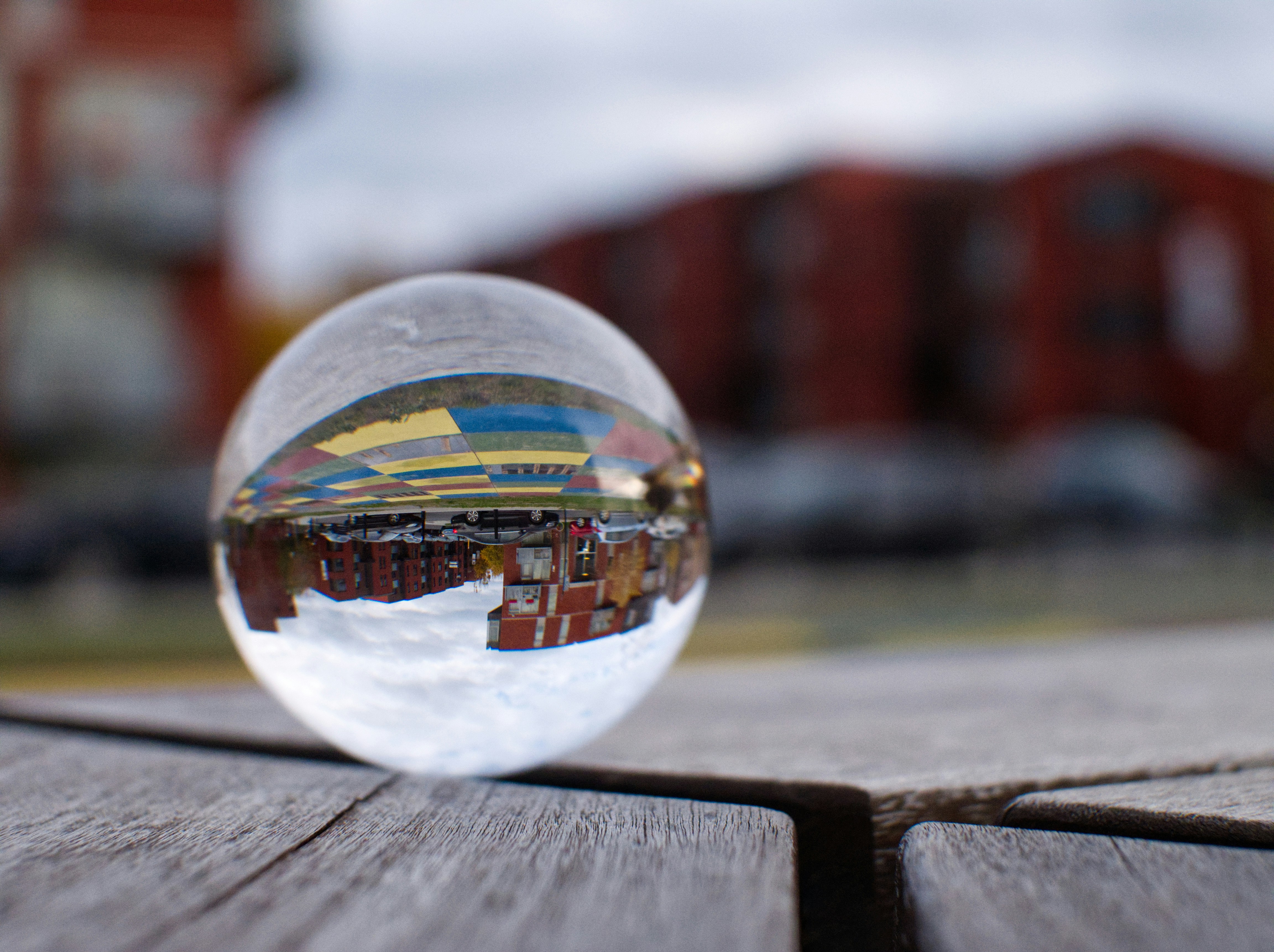 A glass sphere reflecting a colorful urban landscape, with buildings and painted surfaces inverted within it.