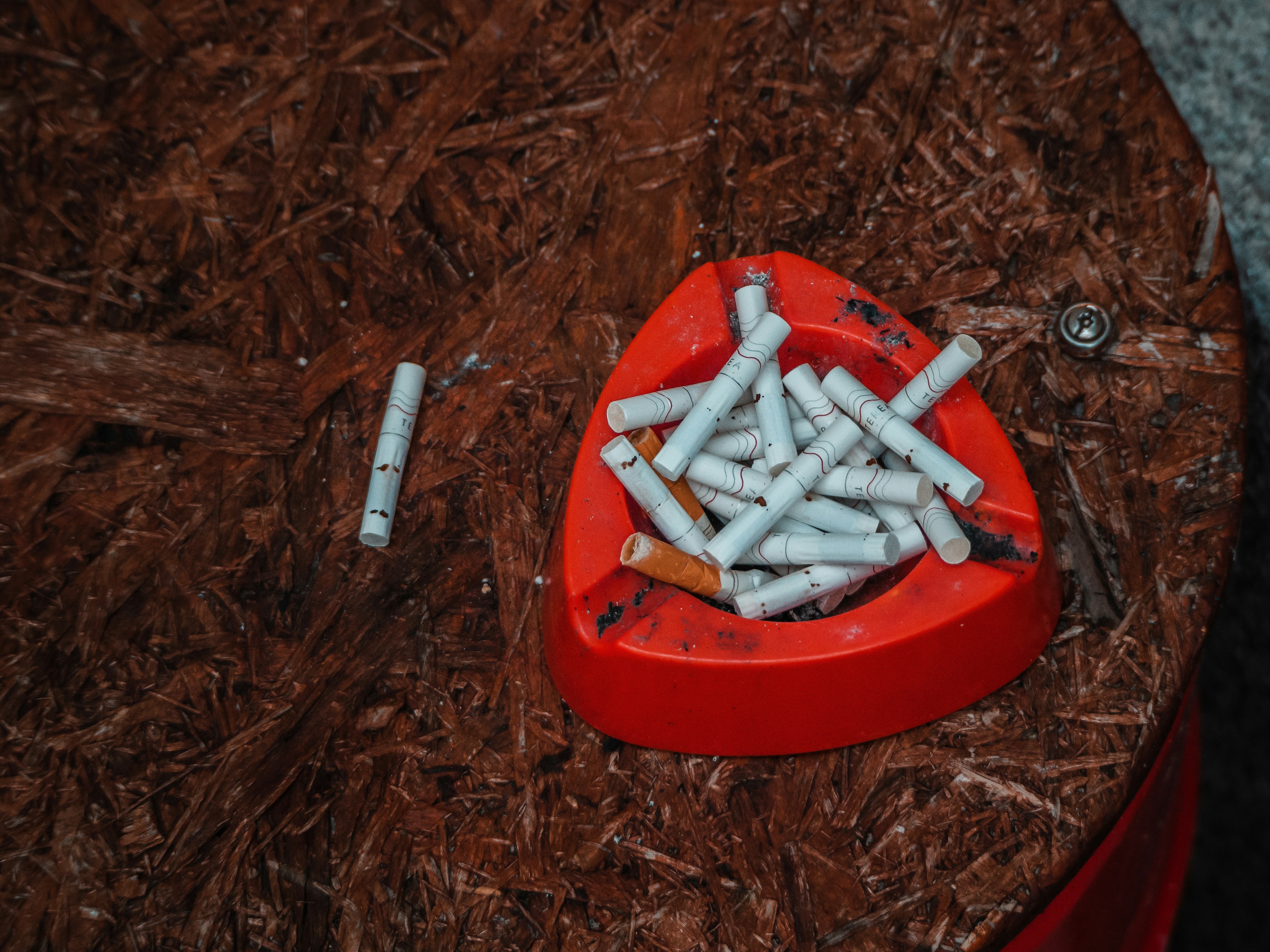 Crimson Heart Ashtray: Cigarette Clutter on Weathered Wood