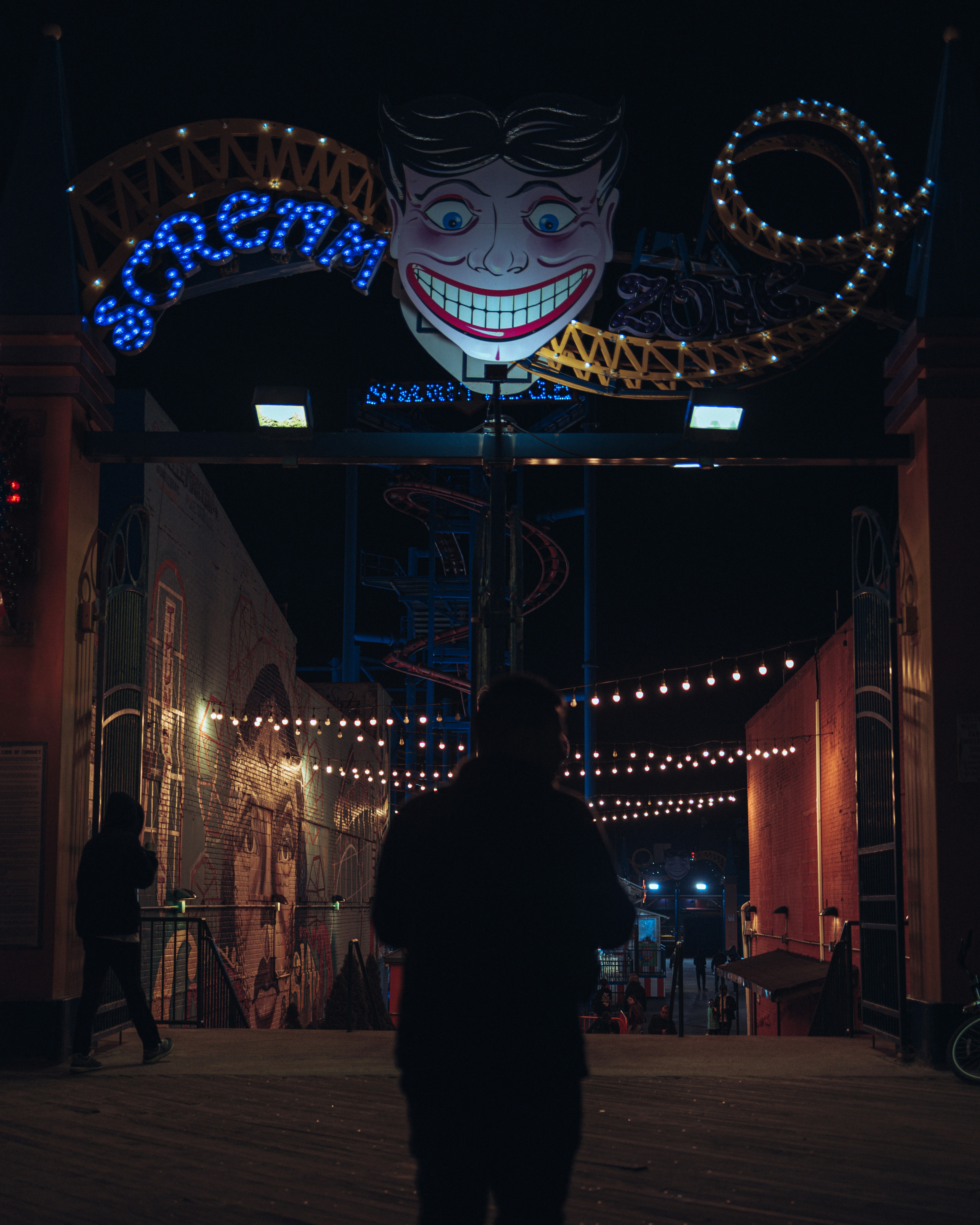 A person walking under a large sign photo – Free Coney island Image on ...