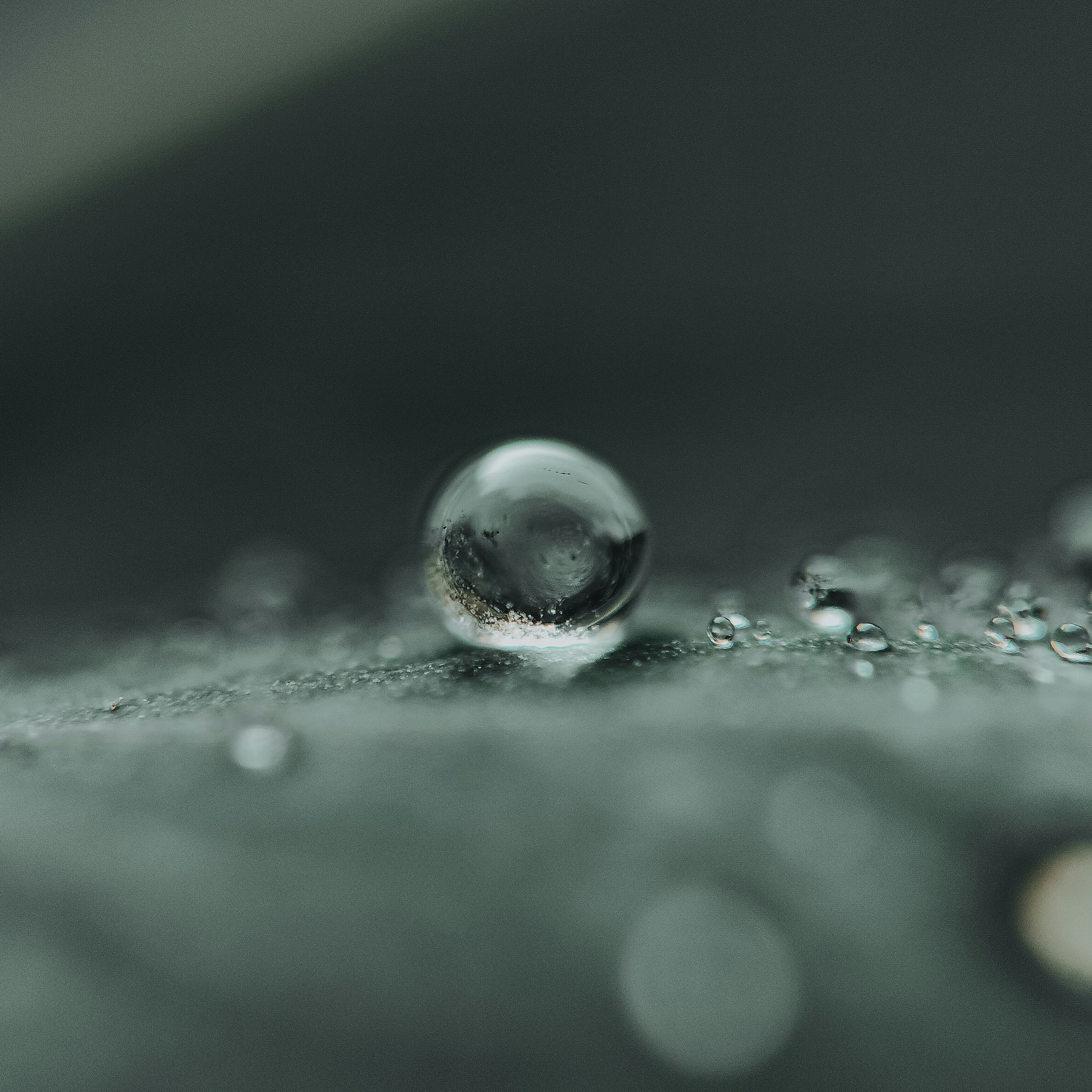 A close-up of a water droplet reflecting its surroundings on a textured surface. The scene highlights the intricate details and clarity of the droplet.