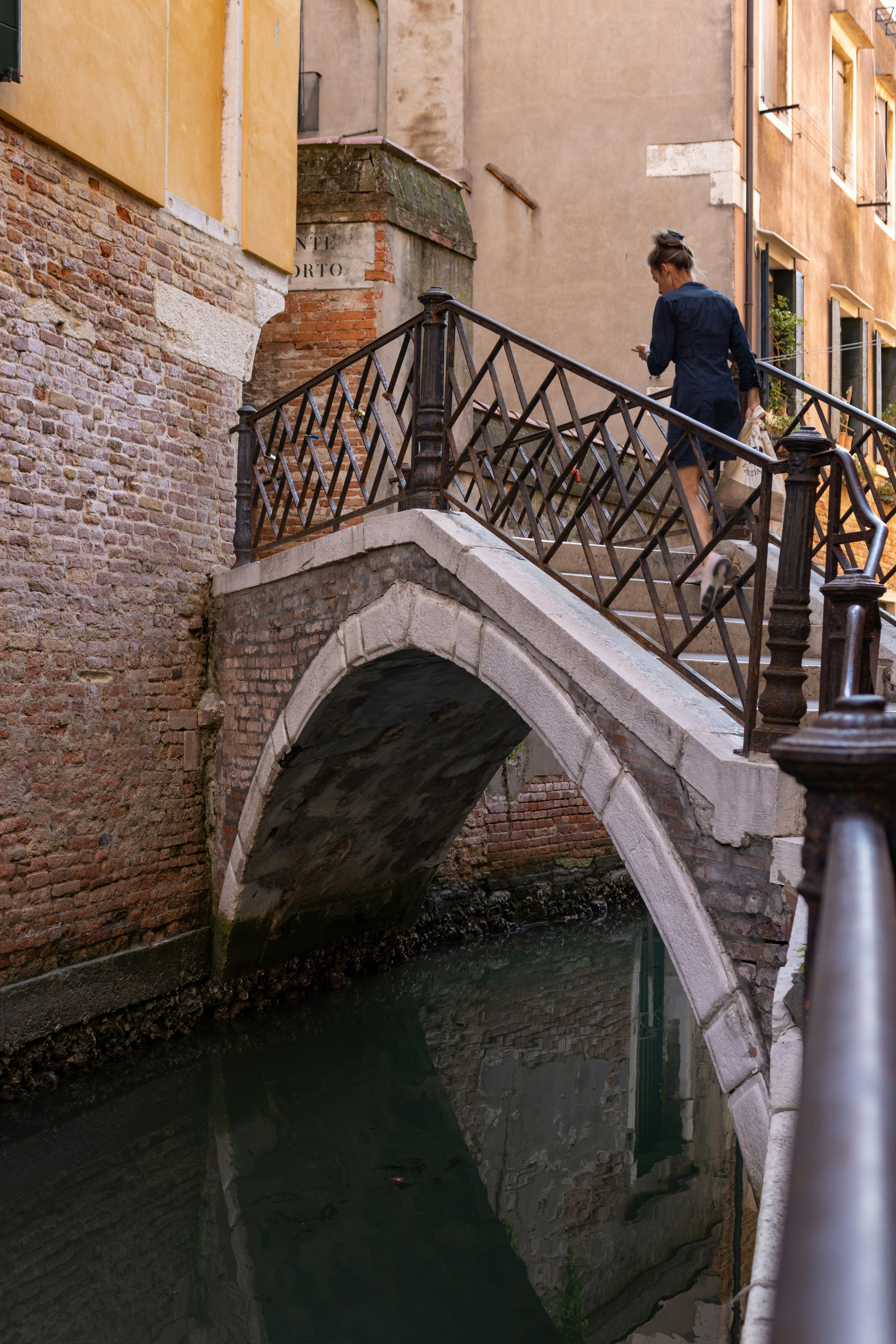Footsteps on a Brick-Arched Canal Bridge Framed by Weathered Facades