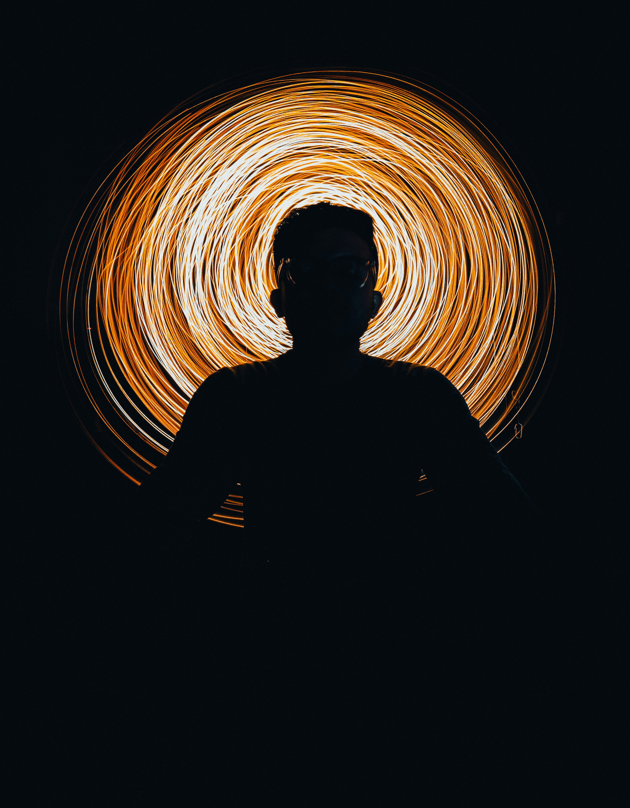 Silhouette of a person surrounded by swirling light trails against a dark background, creating a dynamic contrast.