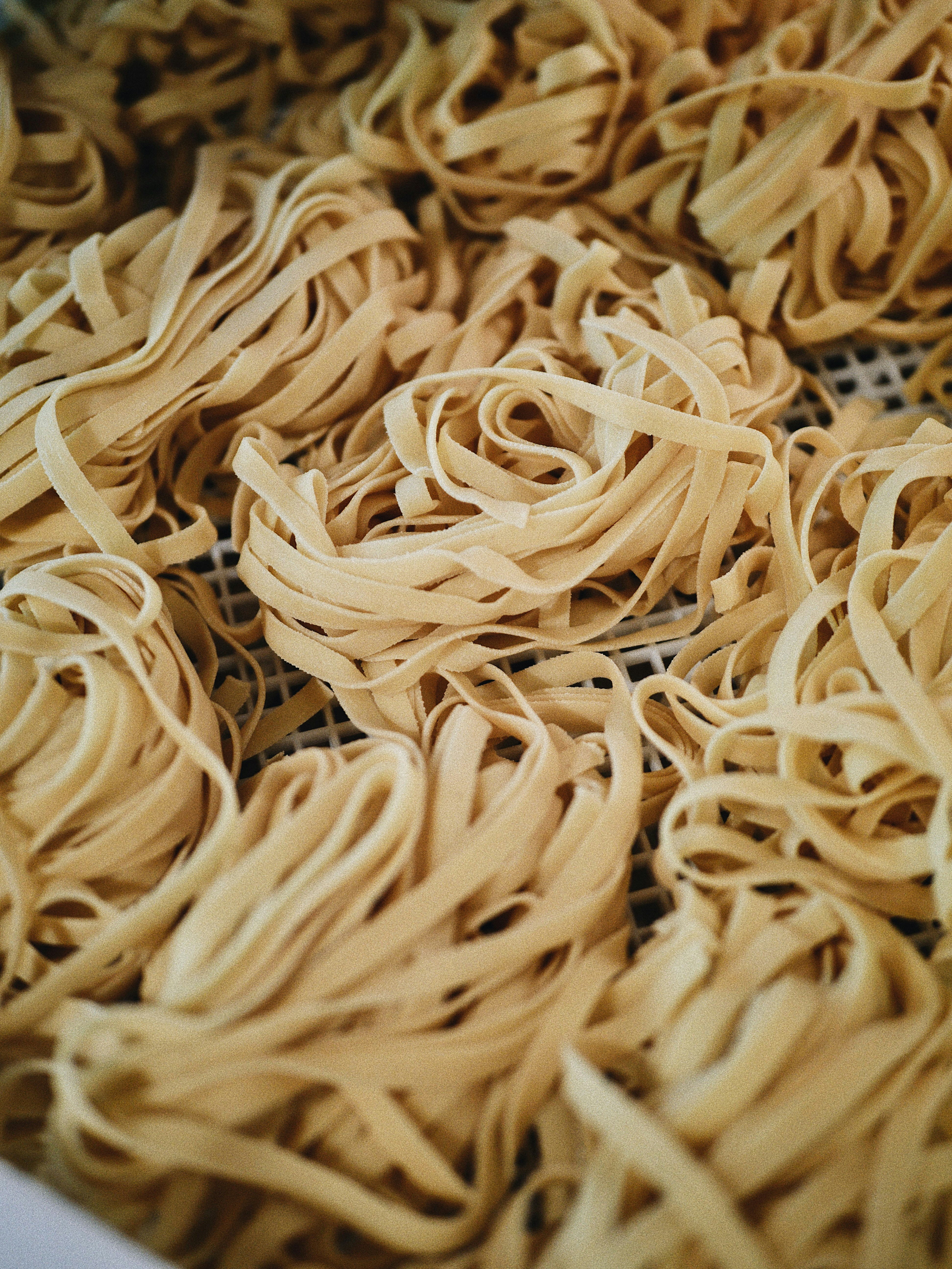Delicate strands of freshly made pasta arranged in an intricate pattern, showcasing the craftsmanship of traditional pasta-making.
