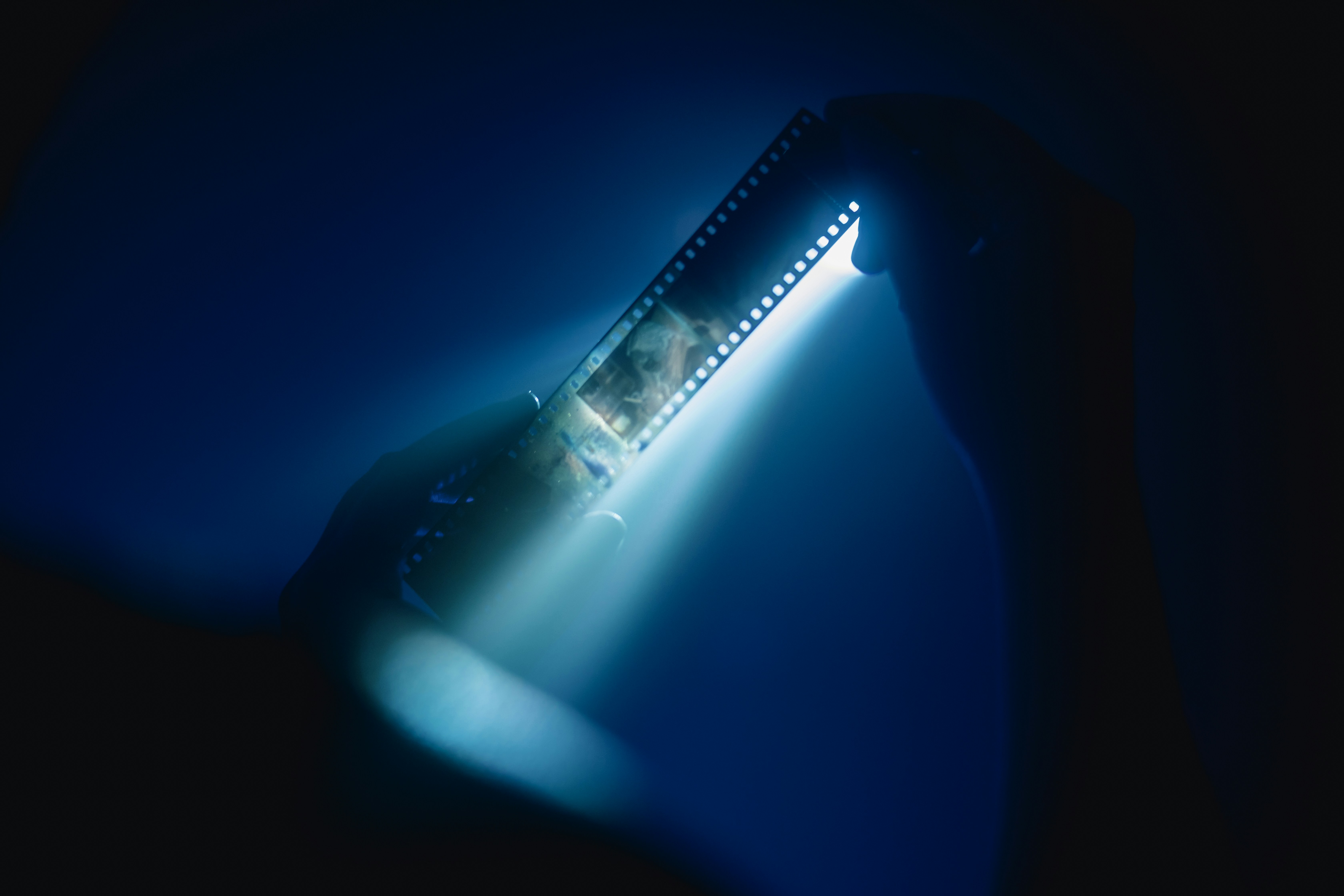 Blue Halation: A Quiet Hand Examines a Film Strip in Low Light