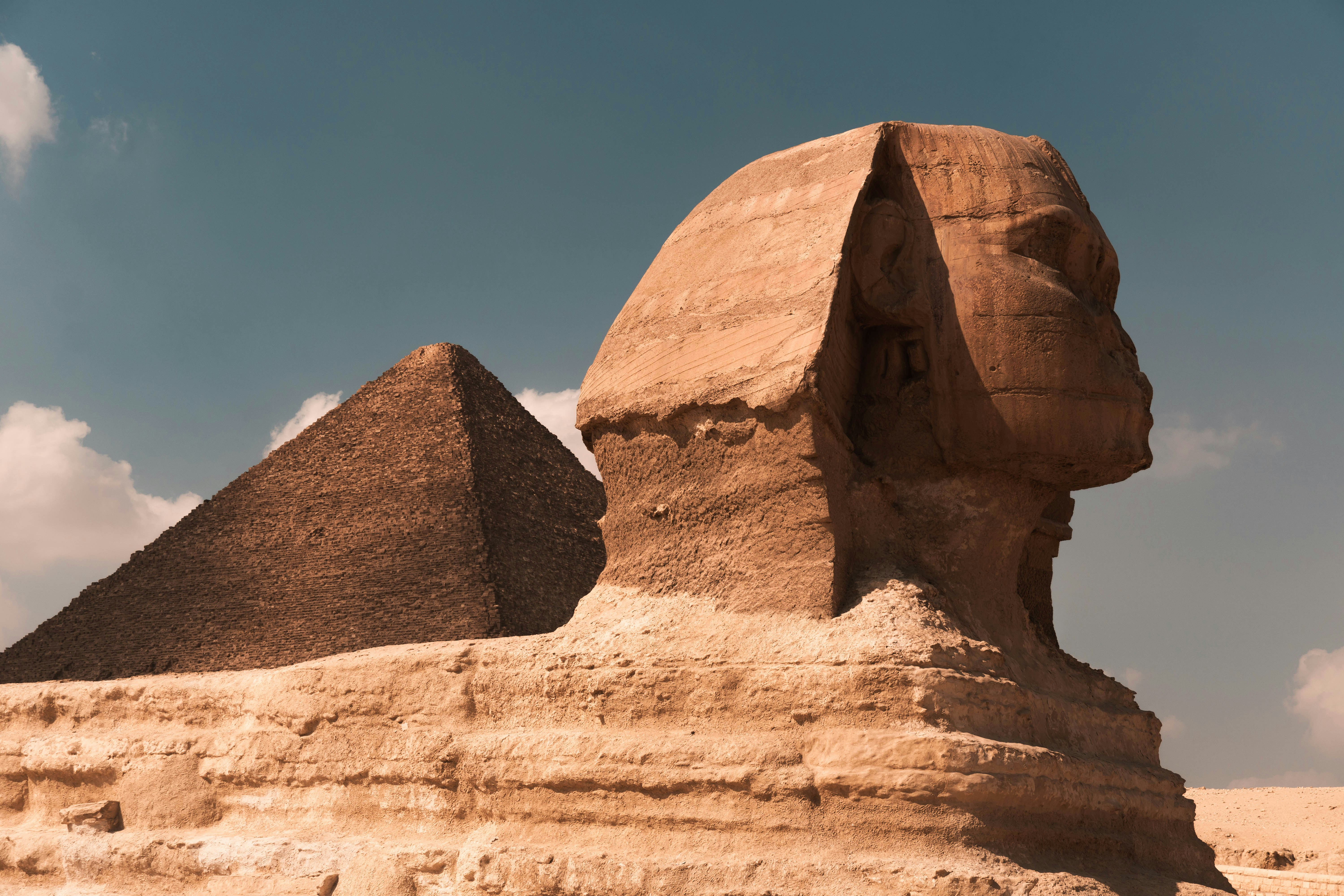 A large rock formation with Great Sphinx of Giza in the background ...