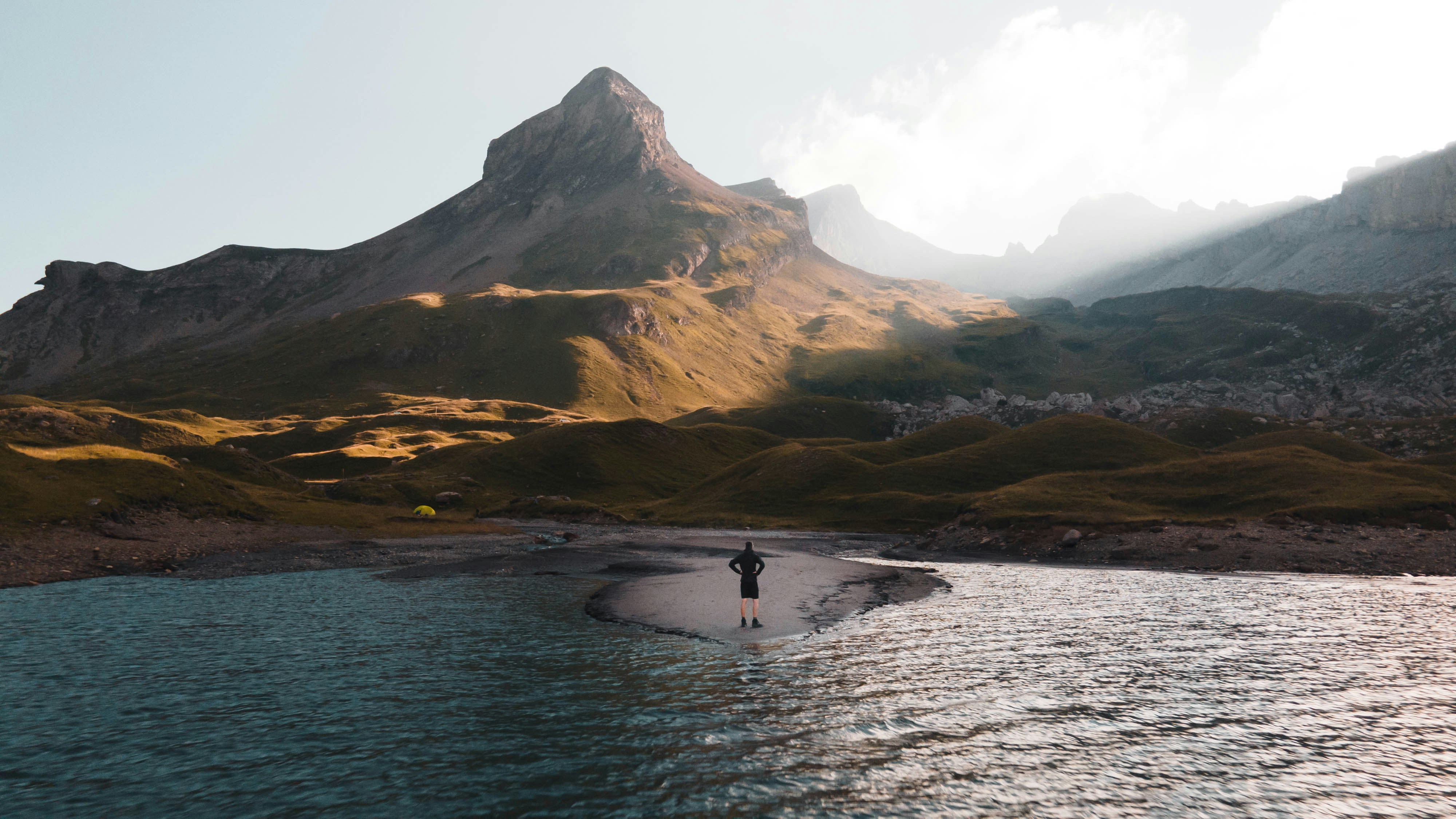 Solo Figure at the Shoreline Under Mountain Ridge