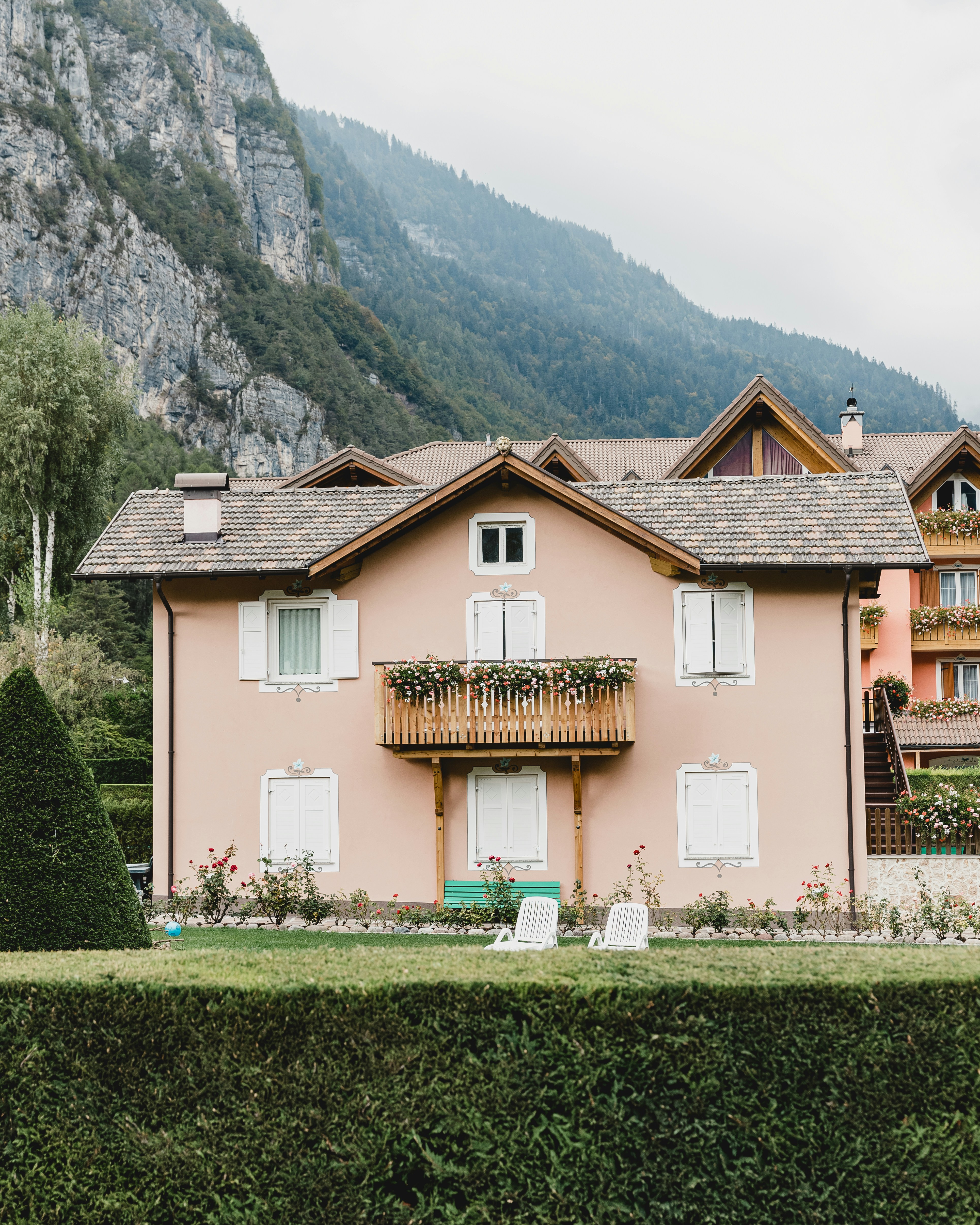 Alpine Peach Chalet: Balcony Blooms Against a Mountain Backdrop