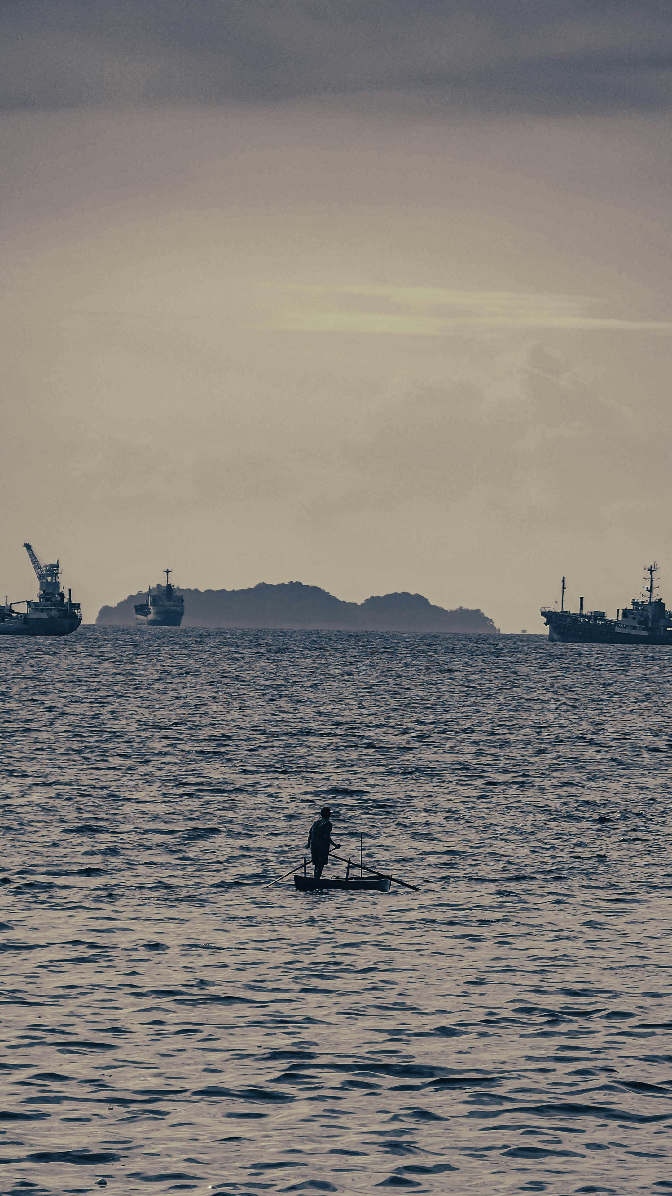Solo Fisherman Between a Calm Sea and a Fleet Horizon