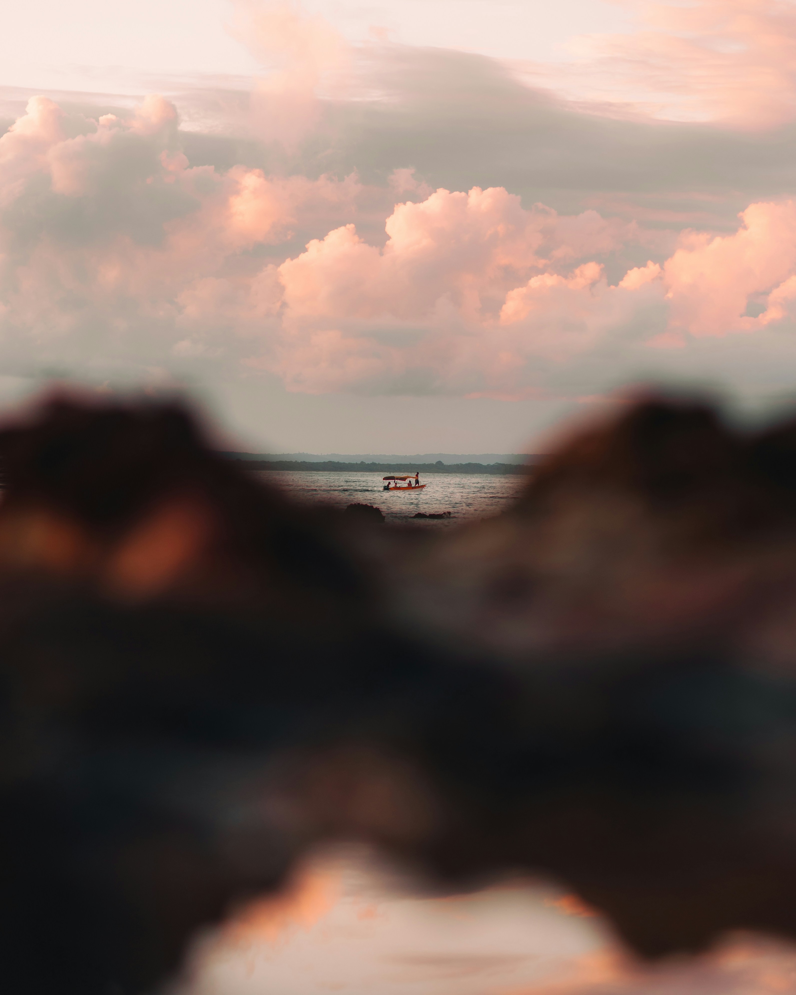 Lone Boat on a Velvet Sea Under Blush Clouds