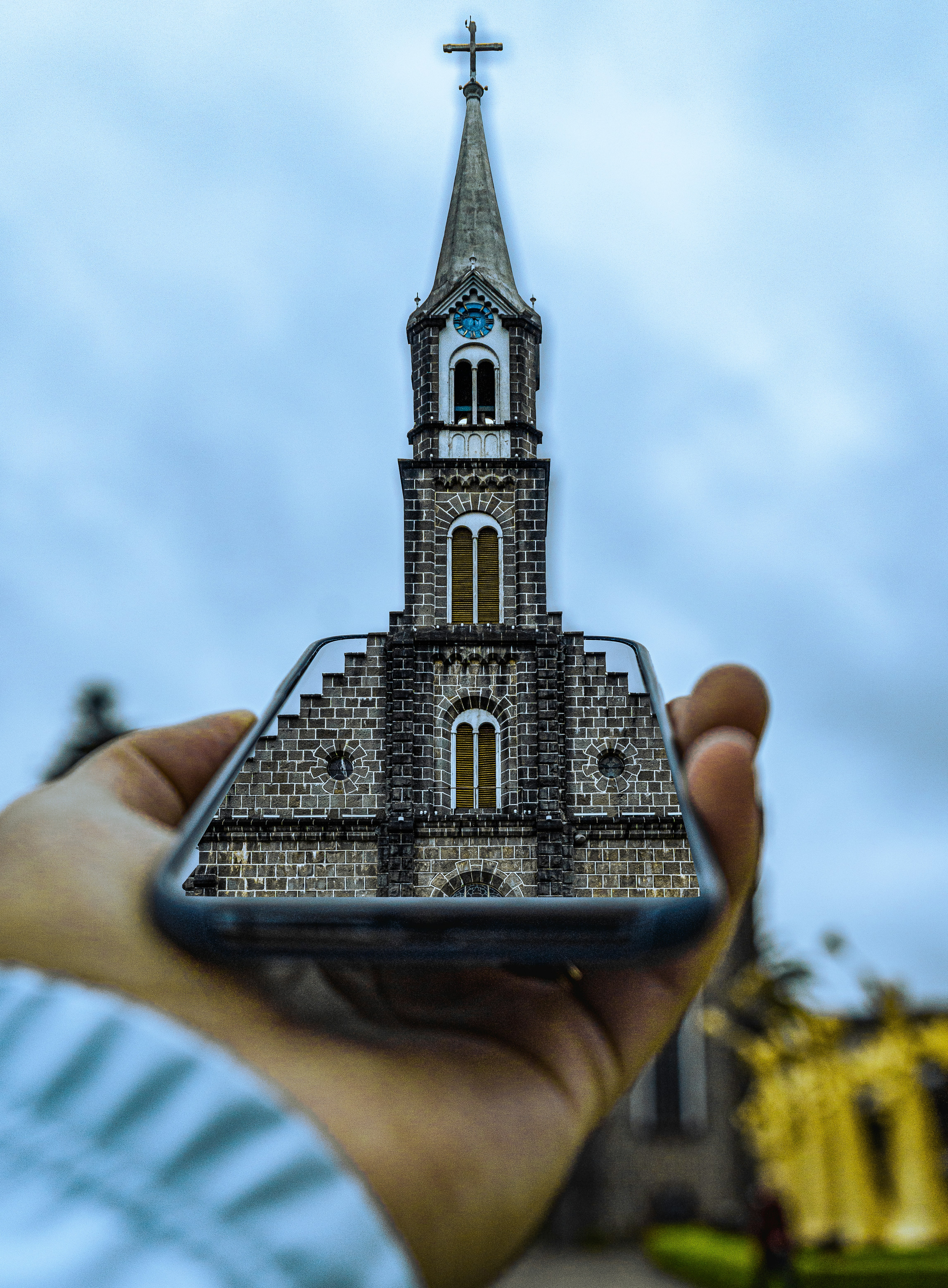 Phone-Frame Cathedral: A Brick Spire Framed by a Handheld Screen
