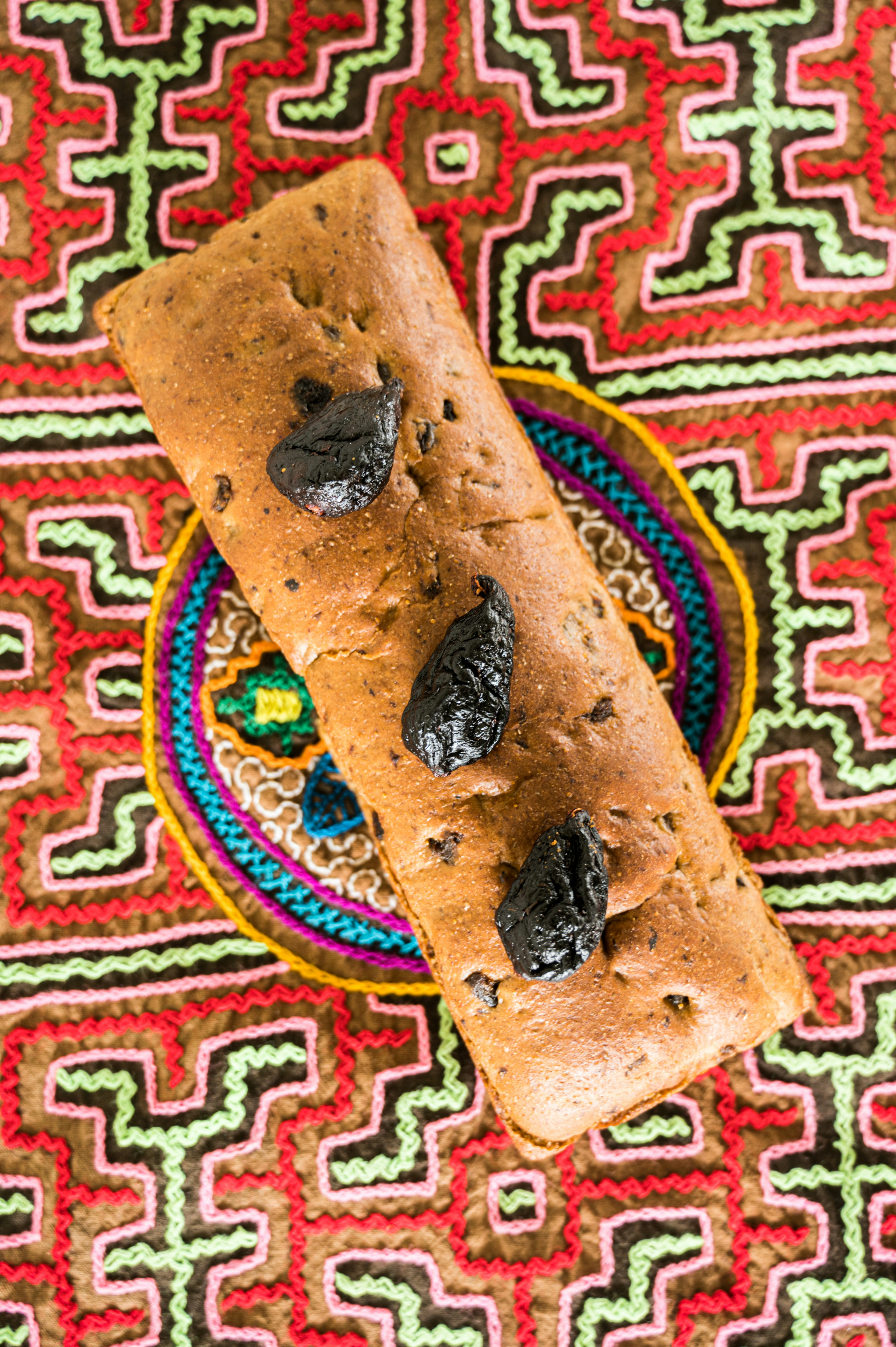 Raisin-studded loaf perched on a vibrant geometric textile centerpiece