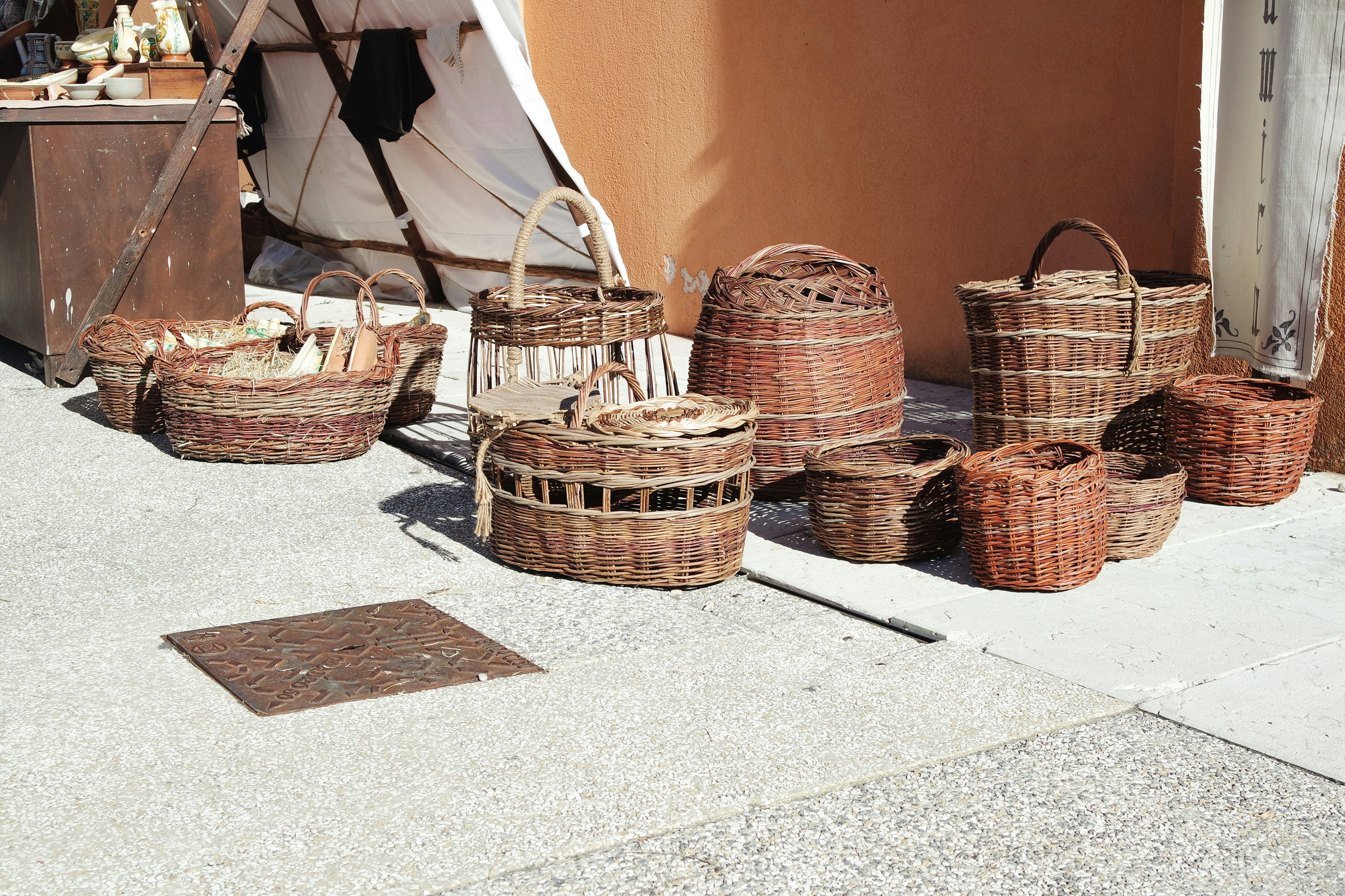 A collection of wicker baskets basking in sunlight against an orange wall.