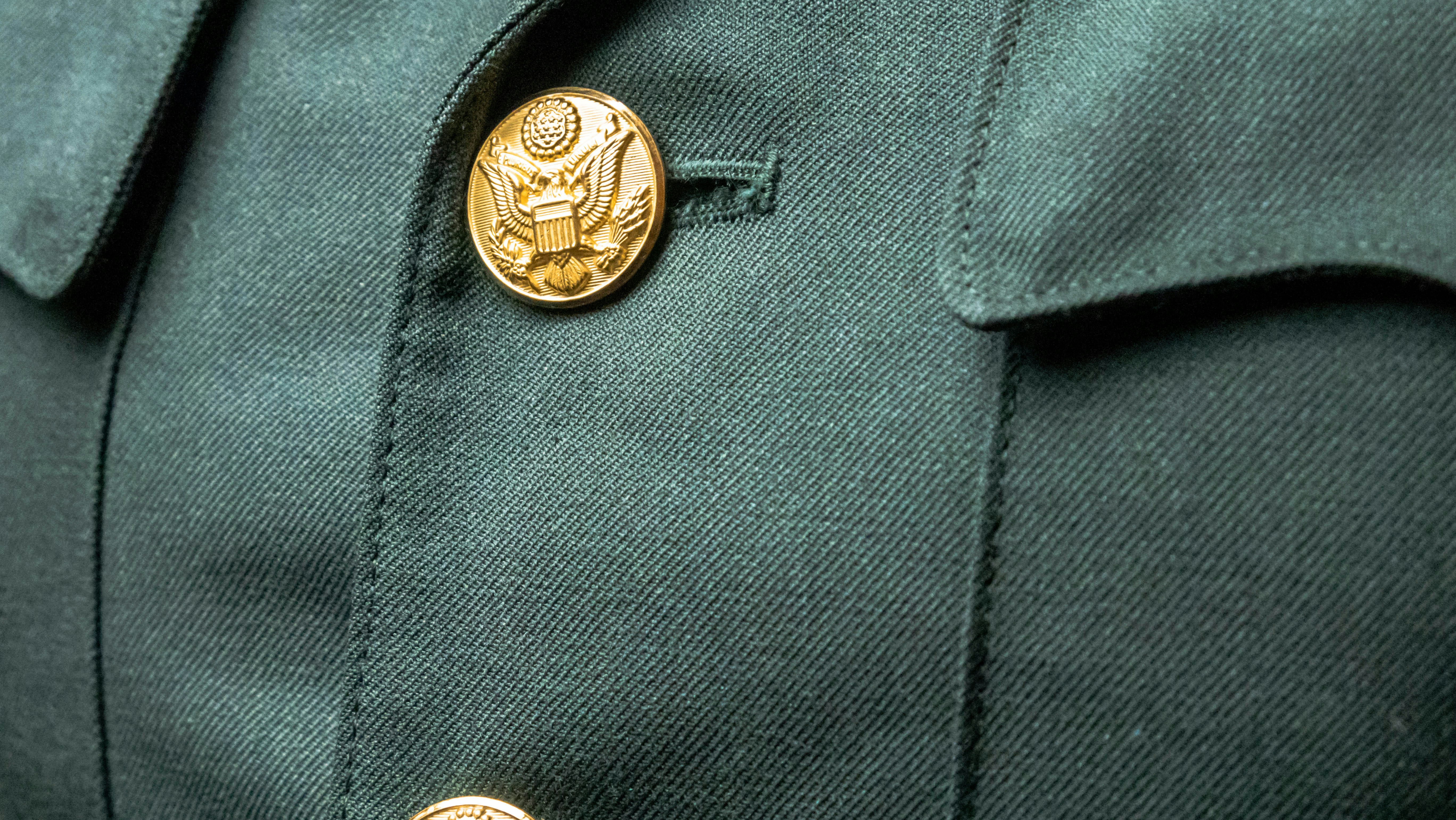 Close-up of military uniform buttons featuring the emblem of the United States, highlighting the intricate design and fabric texture.