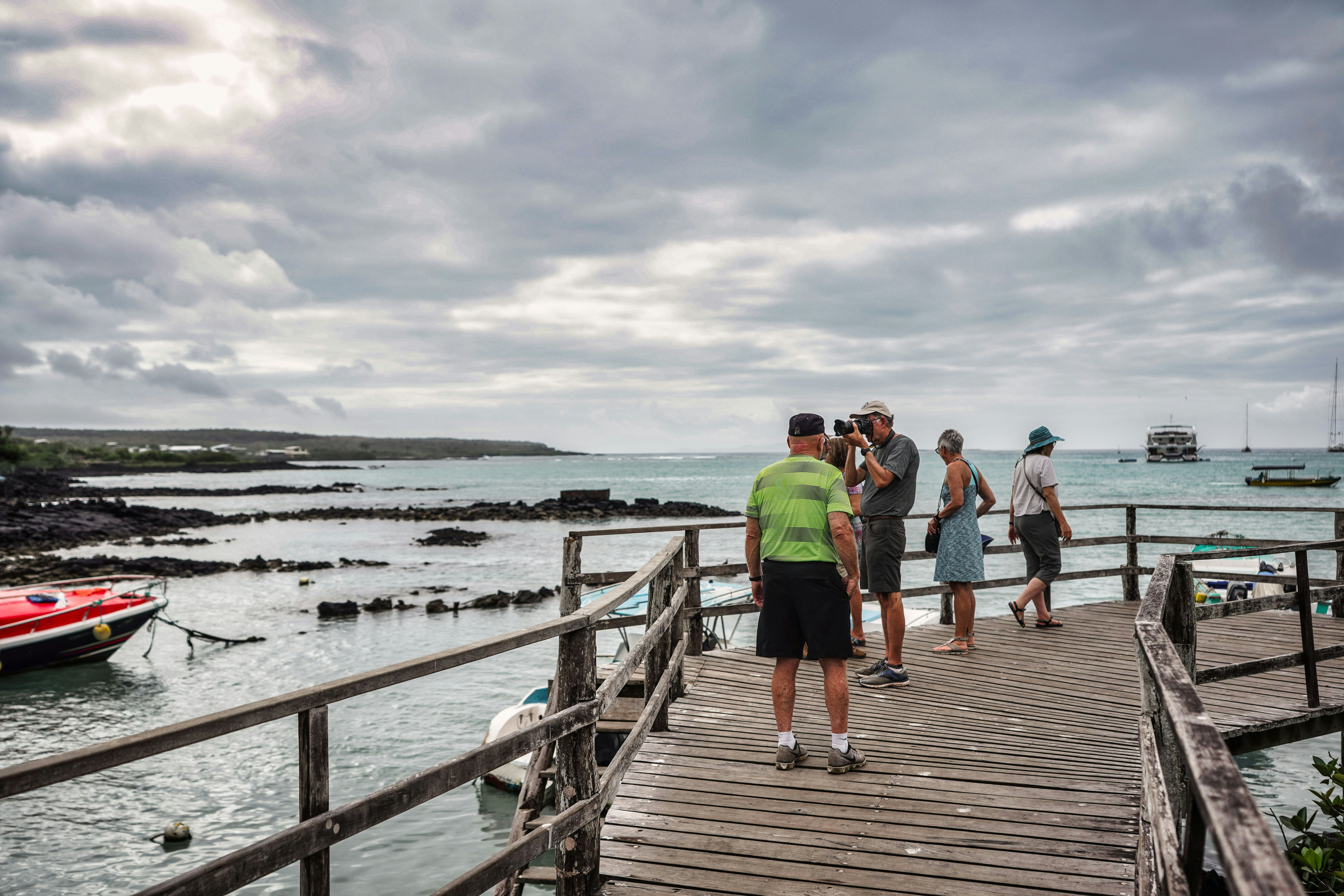 A group of people standing on a dock over water photo – Free Galapagos ...