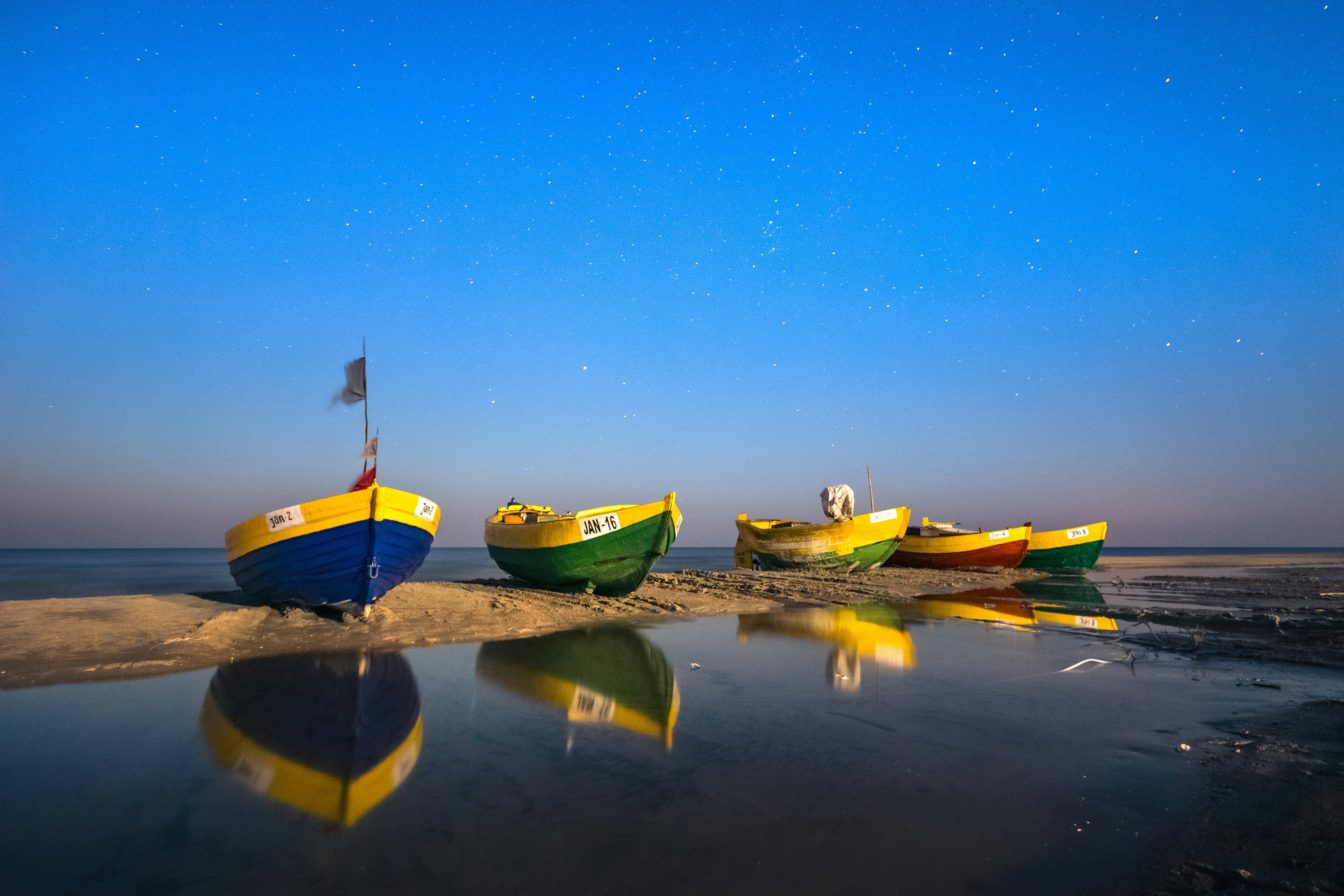 A group of boats sit on the shore of a beach photo – Free Jantar Image ...