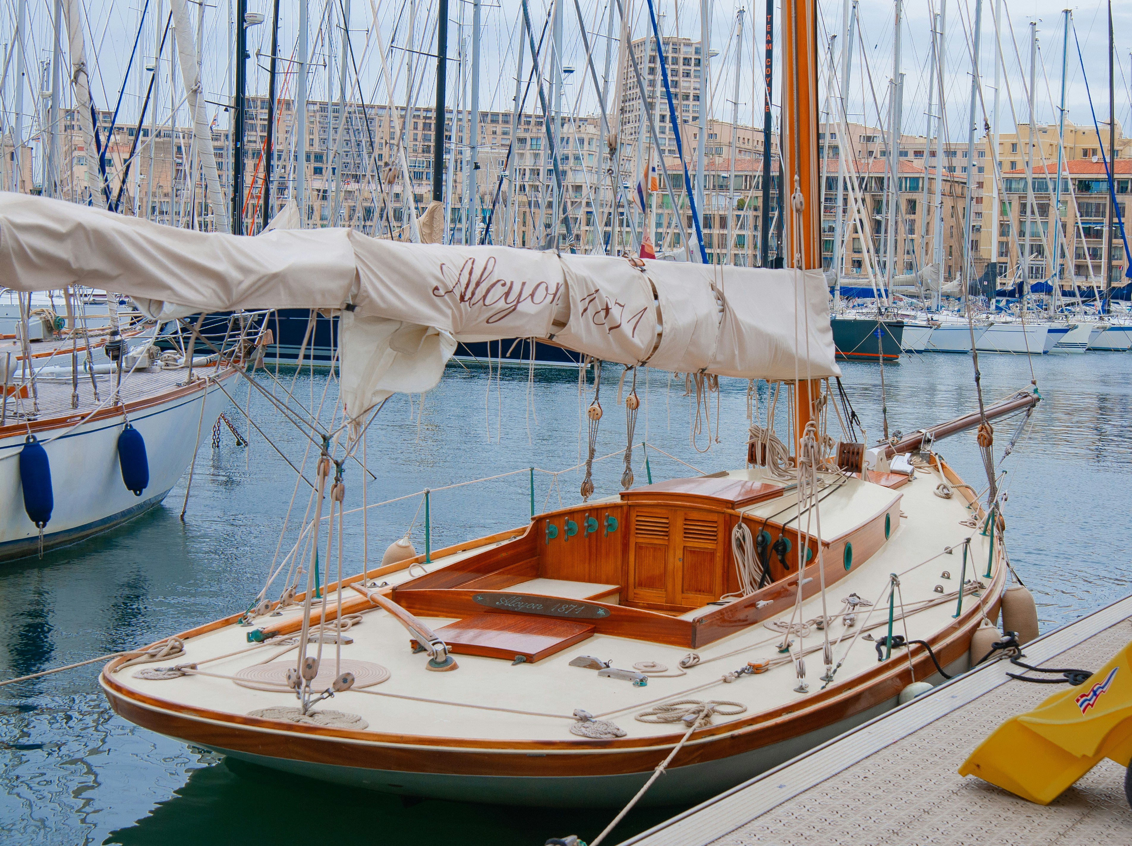 Amber Decks and Sails: A Calm Wooden Sloop at a Modern Marina