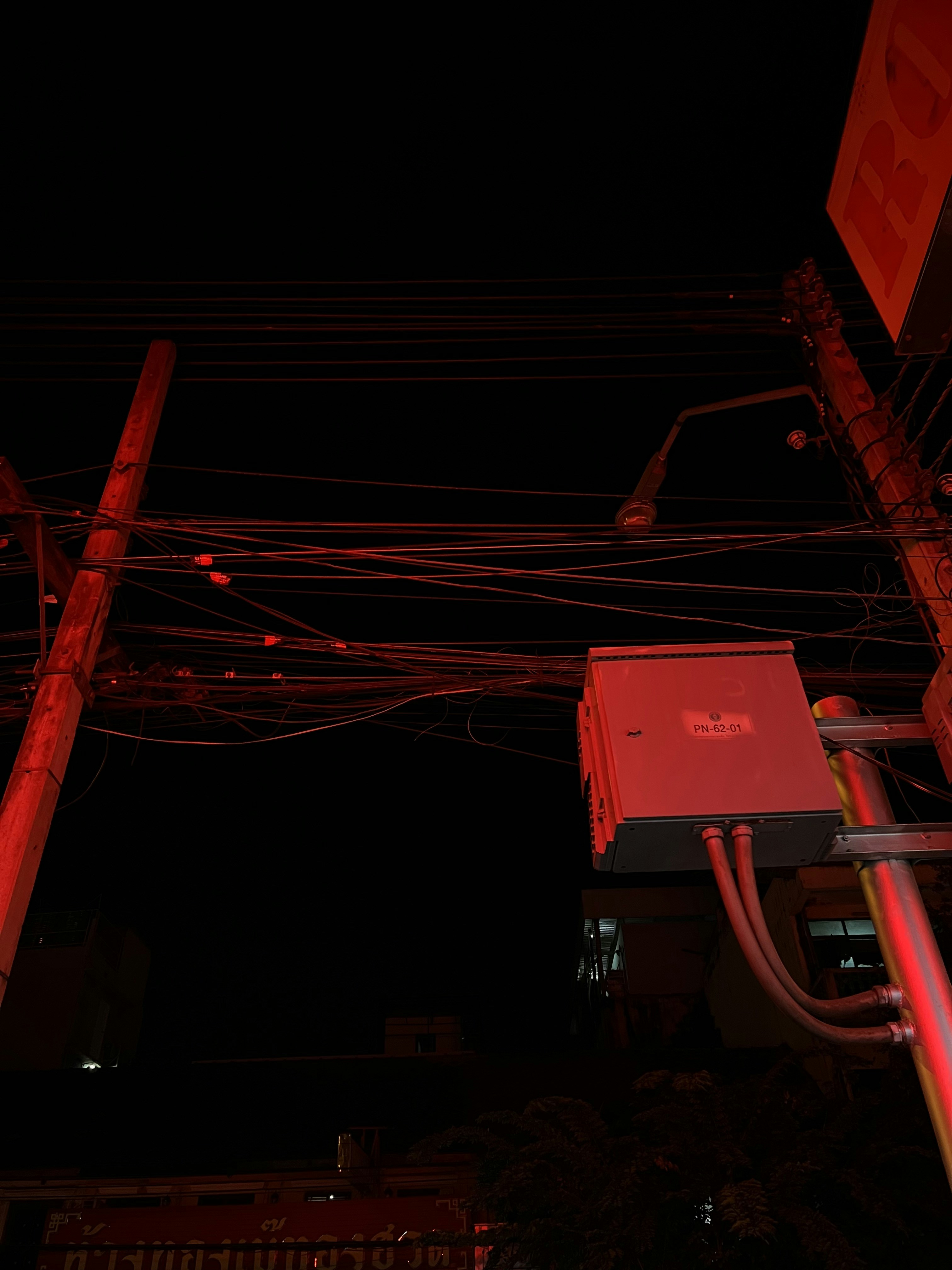 Crimson Webs at Street Level: Power Lines Framing a Lone Transformer