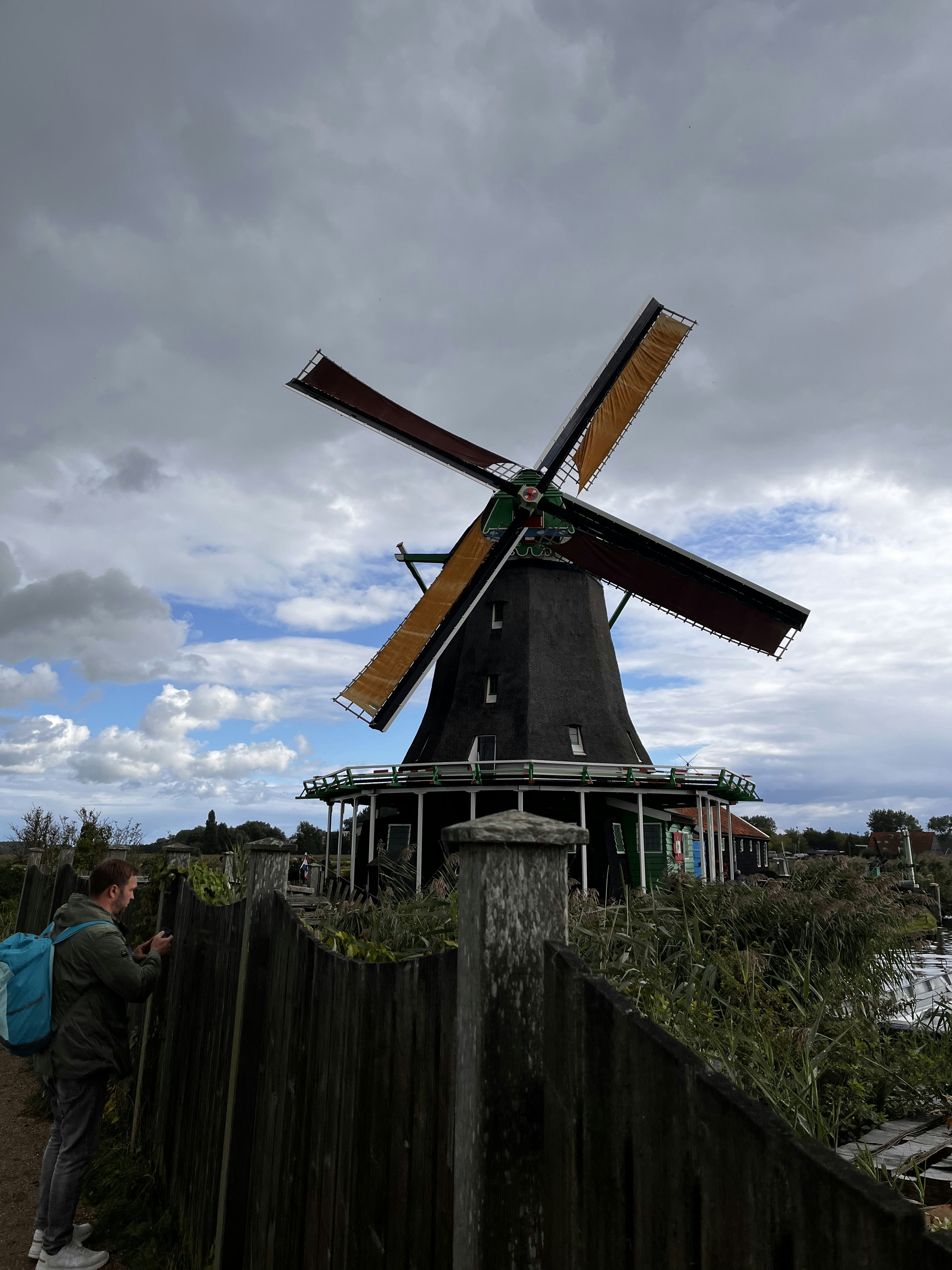 A person standing next to a windmill photo – Free Outdoors Image on ...