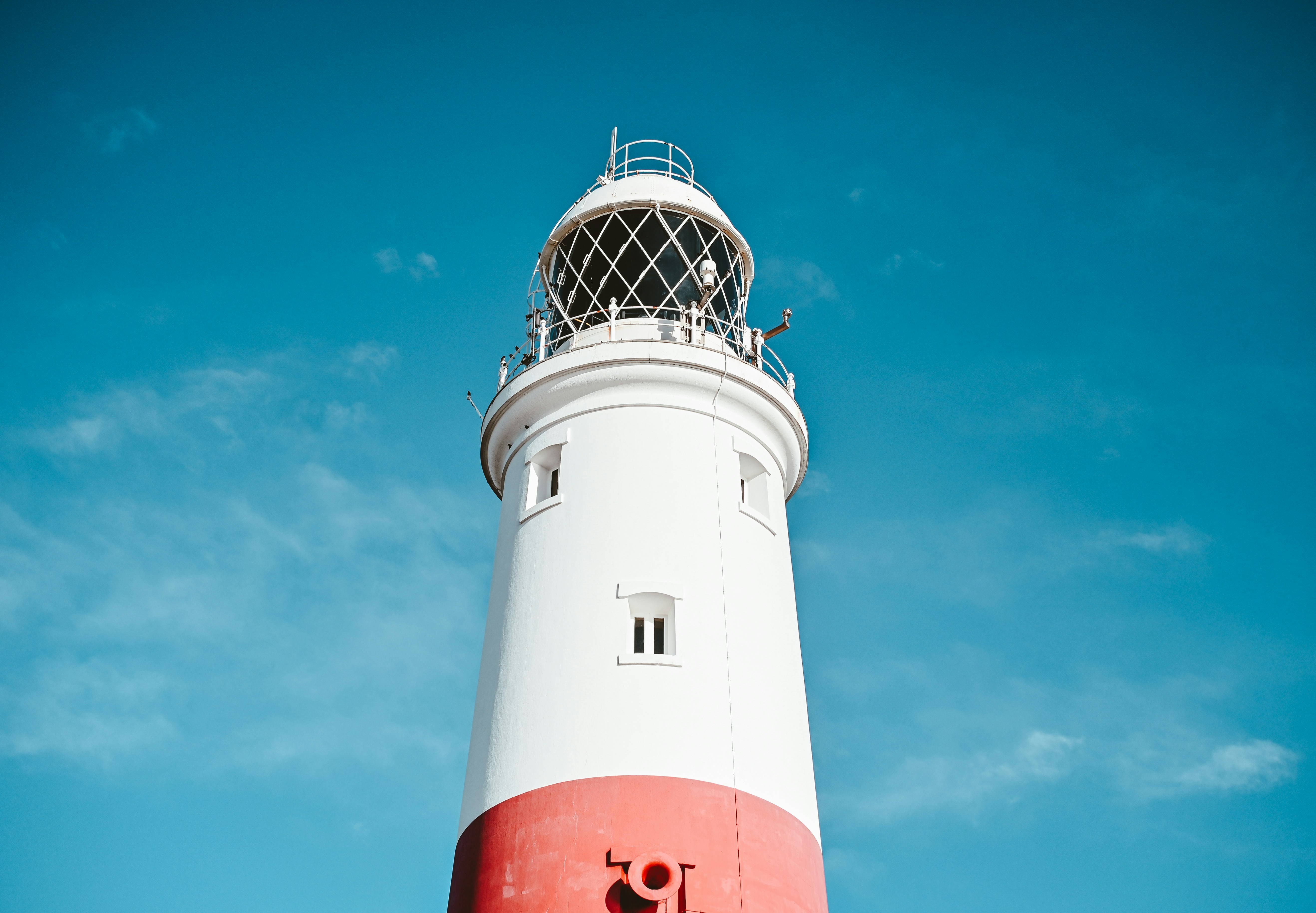 White and red lighthouse tower against a clear blue sky.