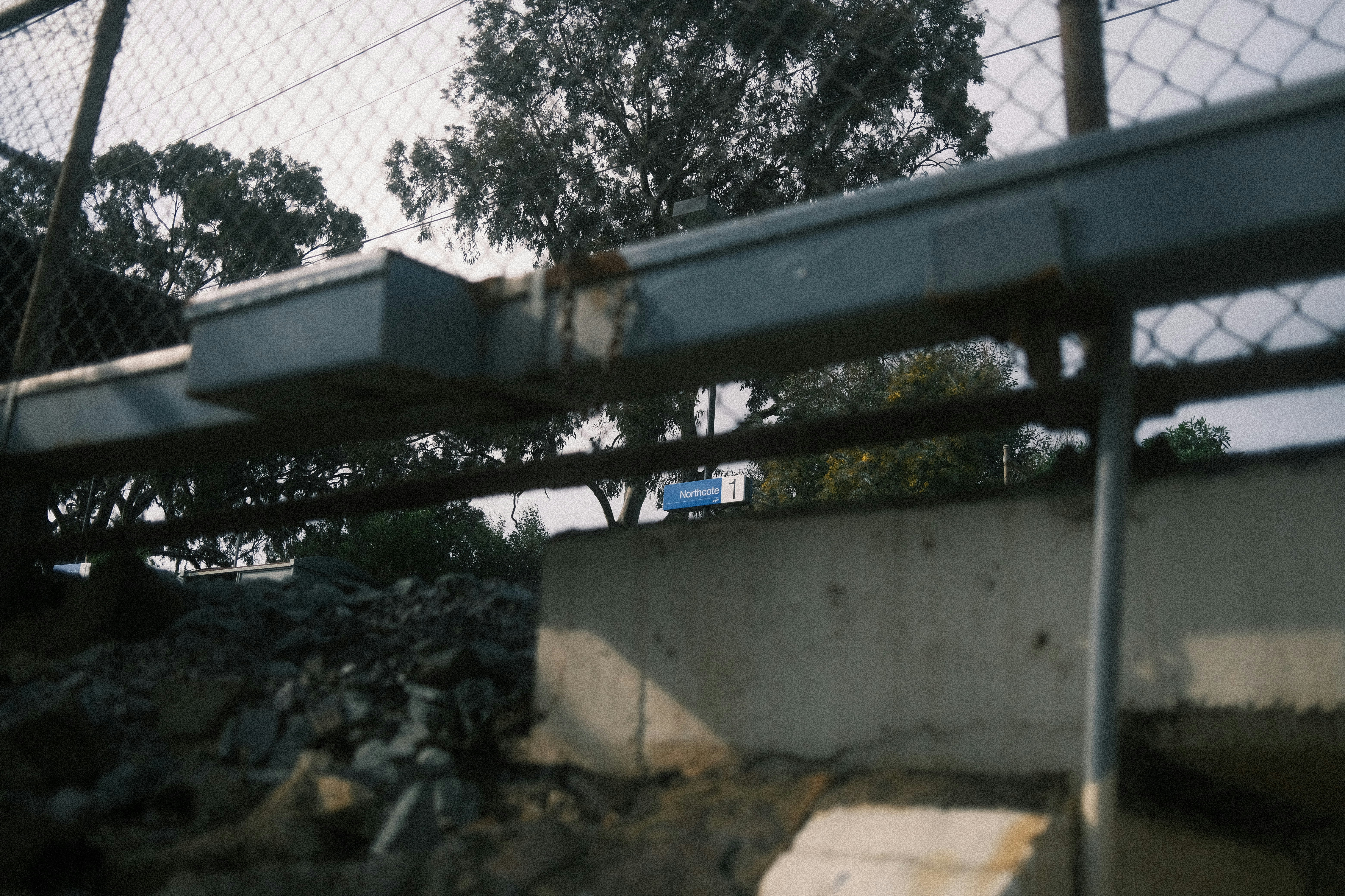 Blue Sign Beyond the Fence: Quiet Geometry of Concrete and Wire