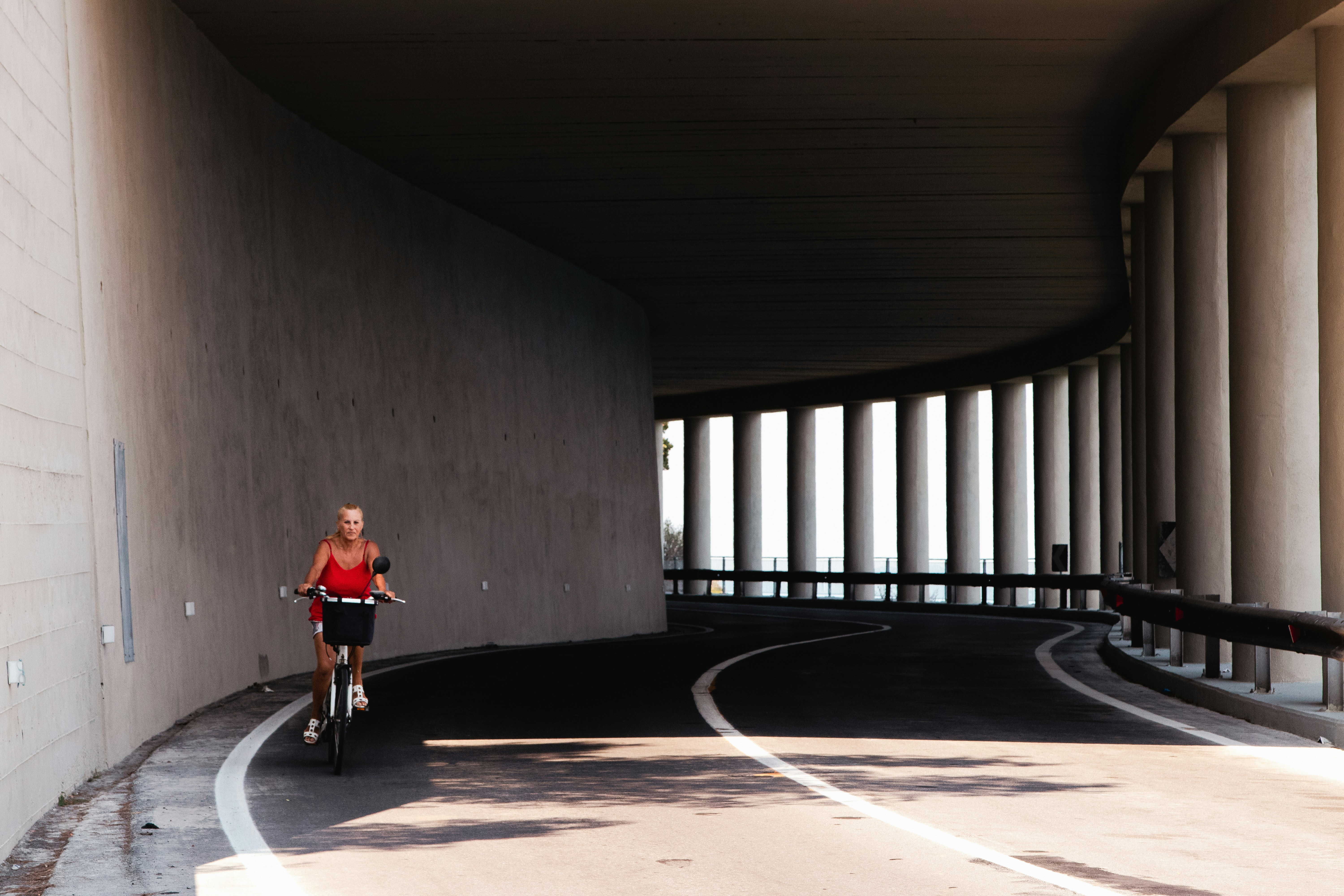 Red-Clad Cyclist Navigates a Sunlit Curve Beneath the Concrete Arc
