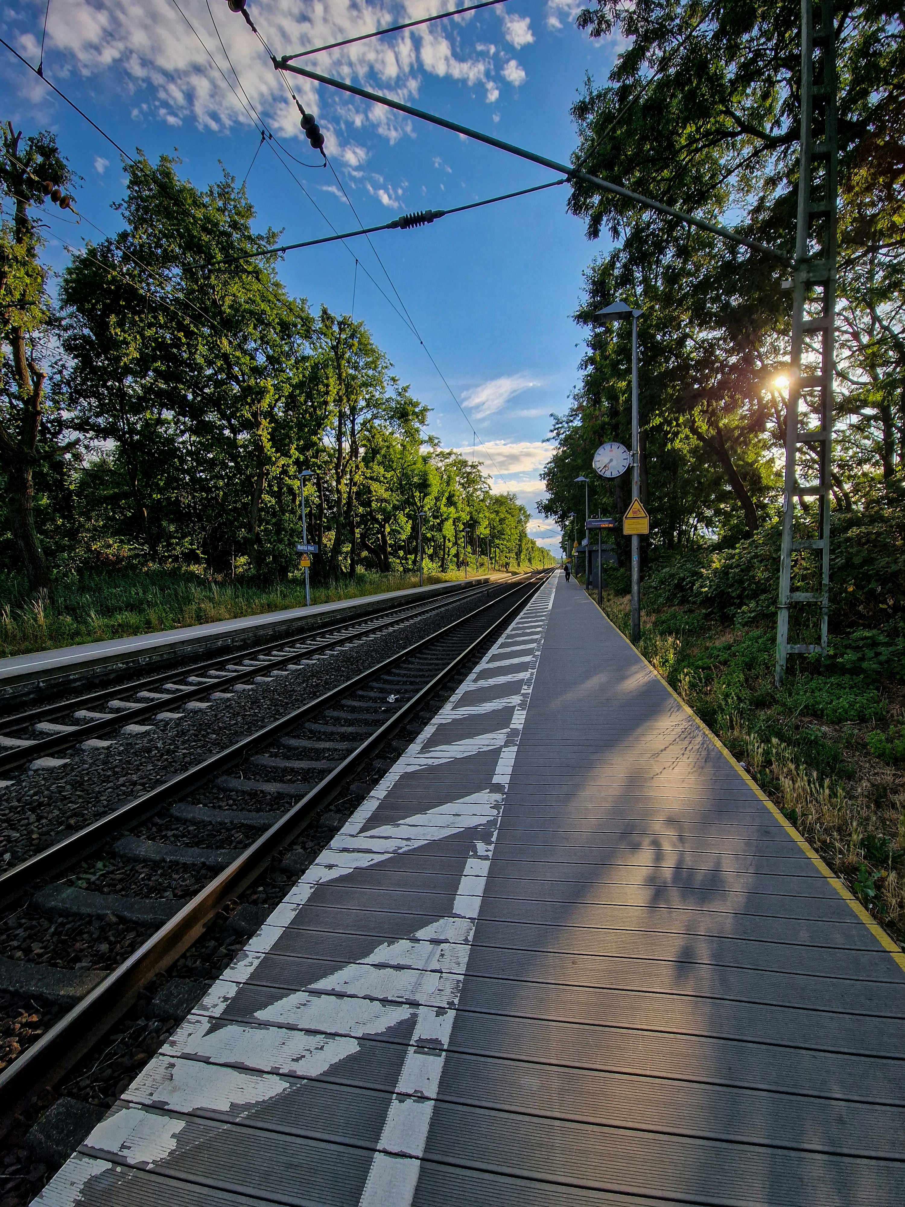 Vanishing Rails: Sunlit Platform Reaching Toward a Green Horizon