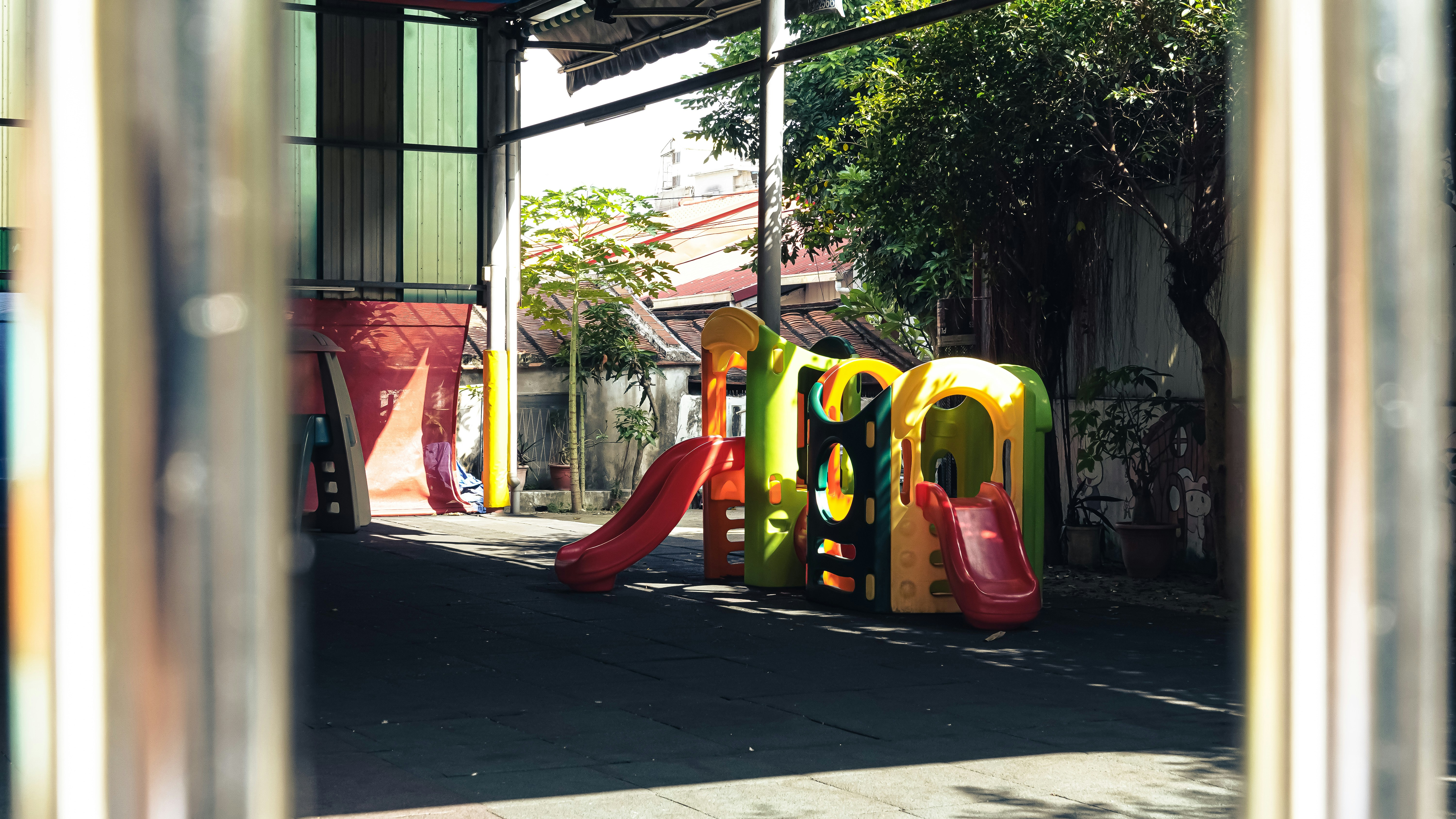 Colorful Play Structures Framed by Quiet Shadows in a Courtyard