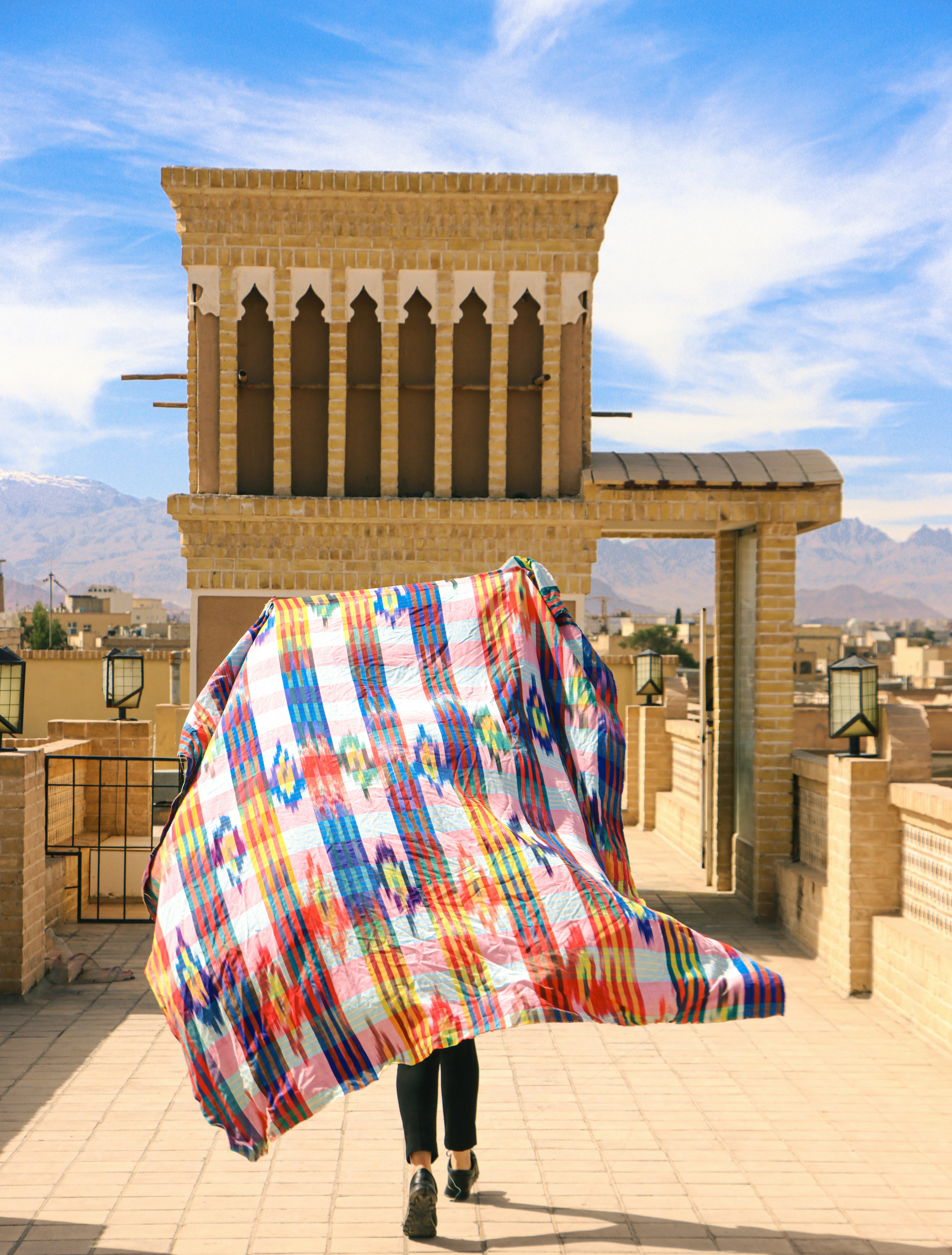 Colorful shawl in motion shields the city ruin from a sunlit alpenglow